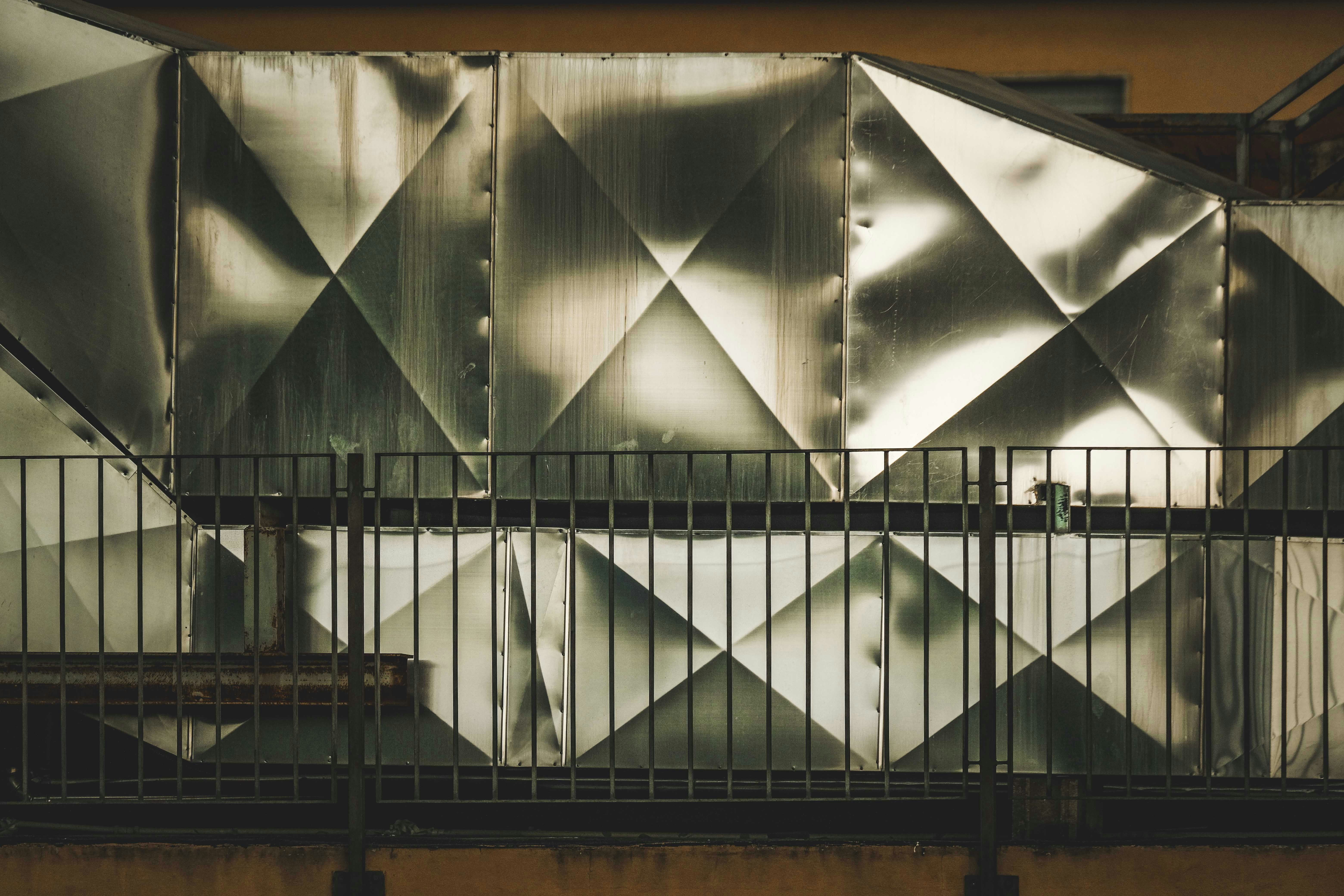 Diamond-Patterned Metal Facade Framed by a City Balcony Rail