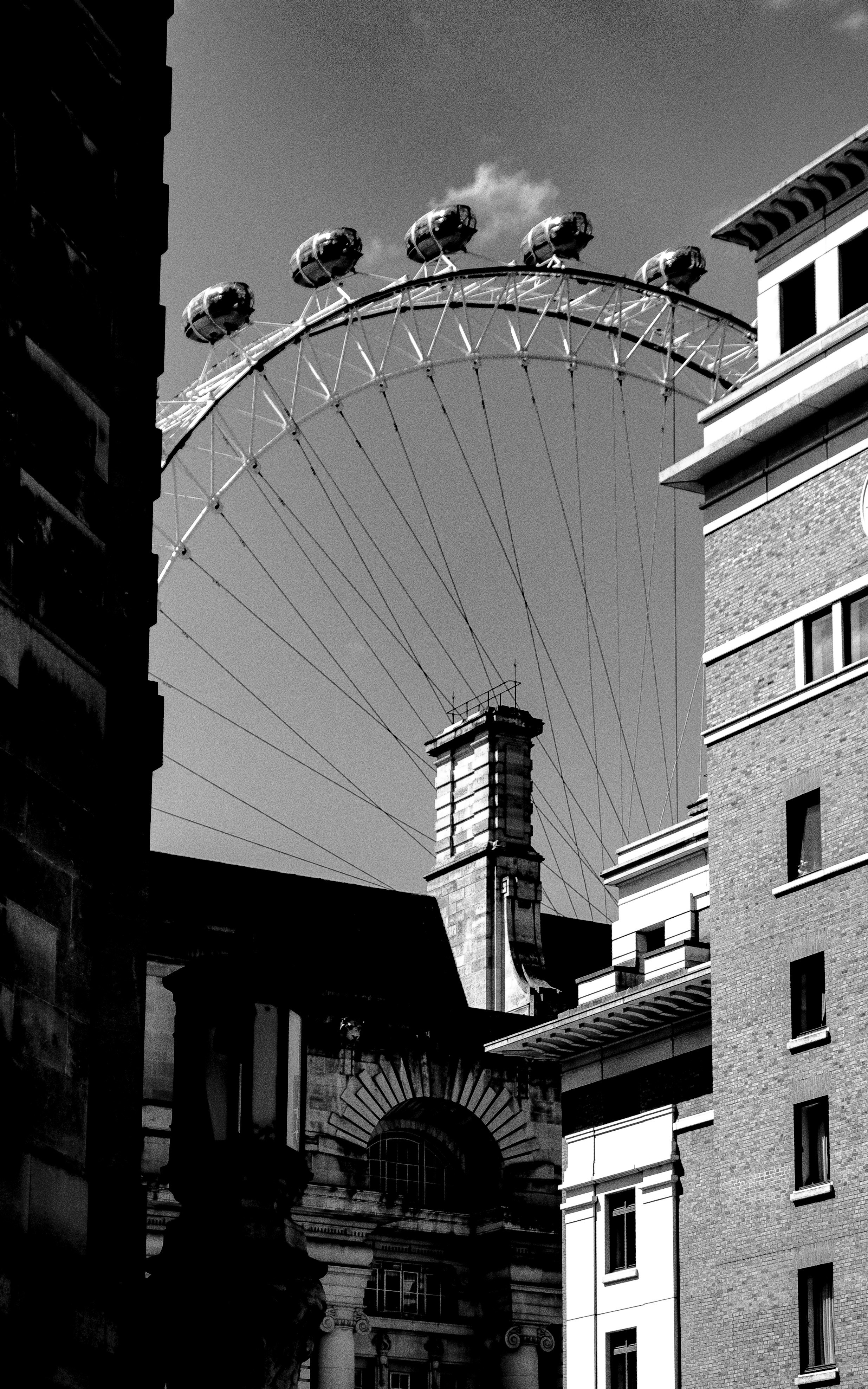 Between Brick and Skyline: The London Eye Peers Over a Narrow City Vista