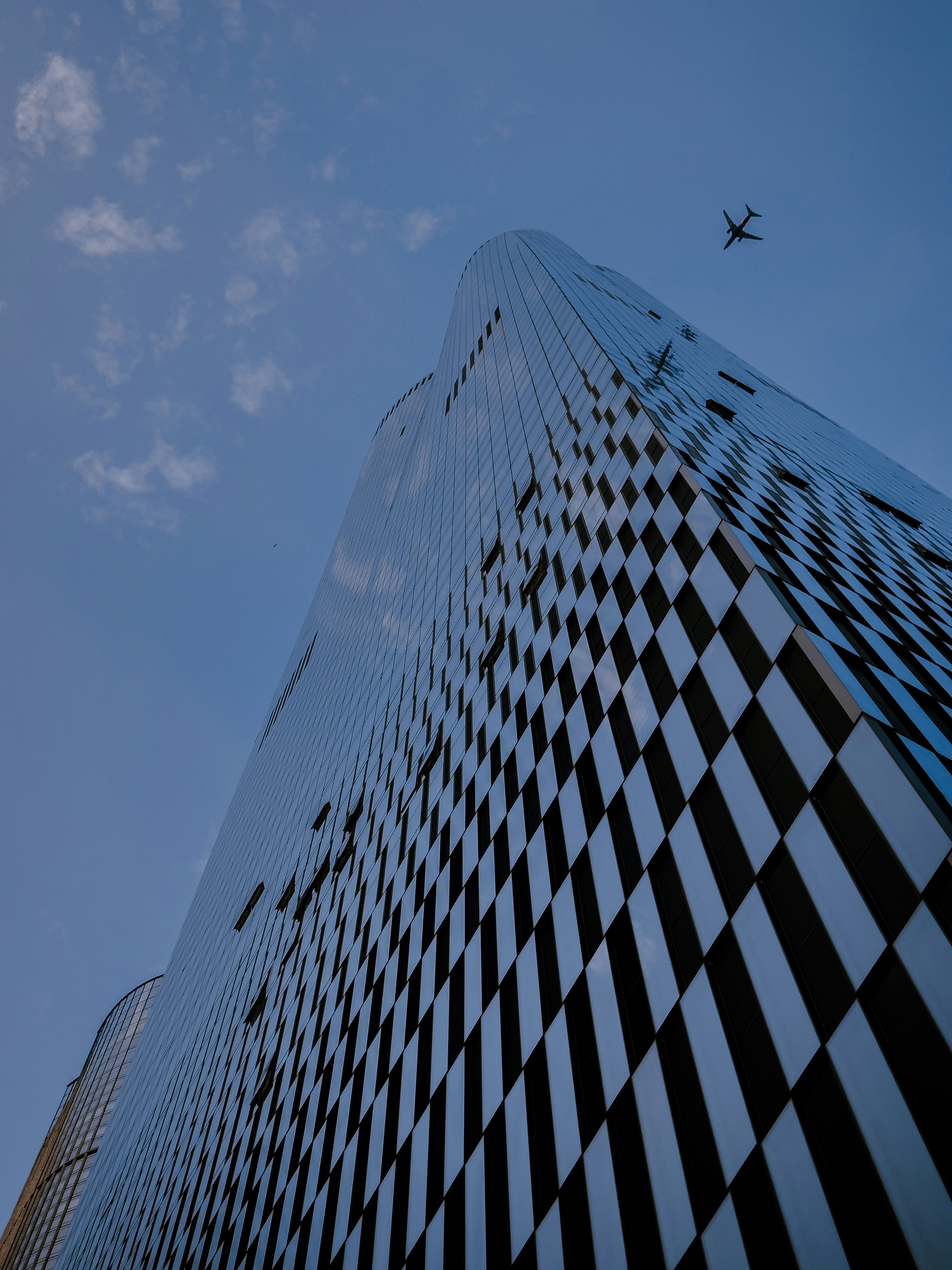 A plane flying over a tall building with a checkerboard design photo ...