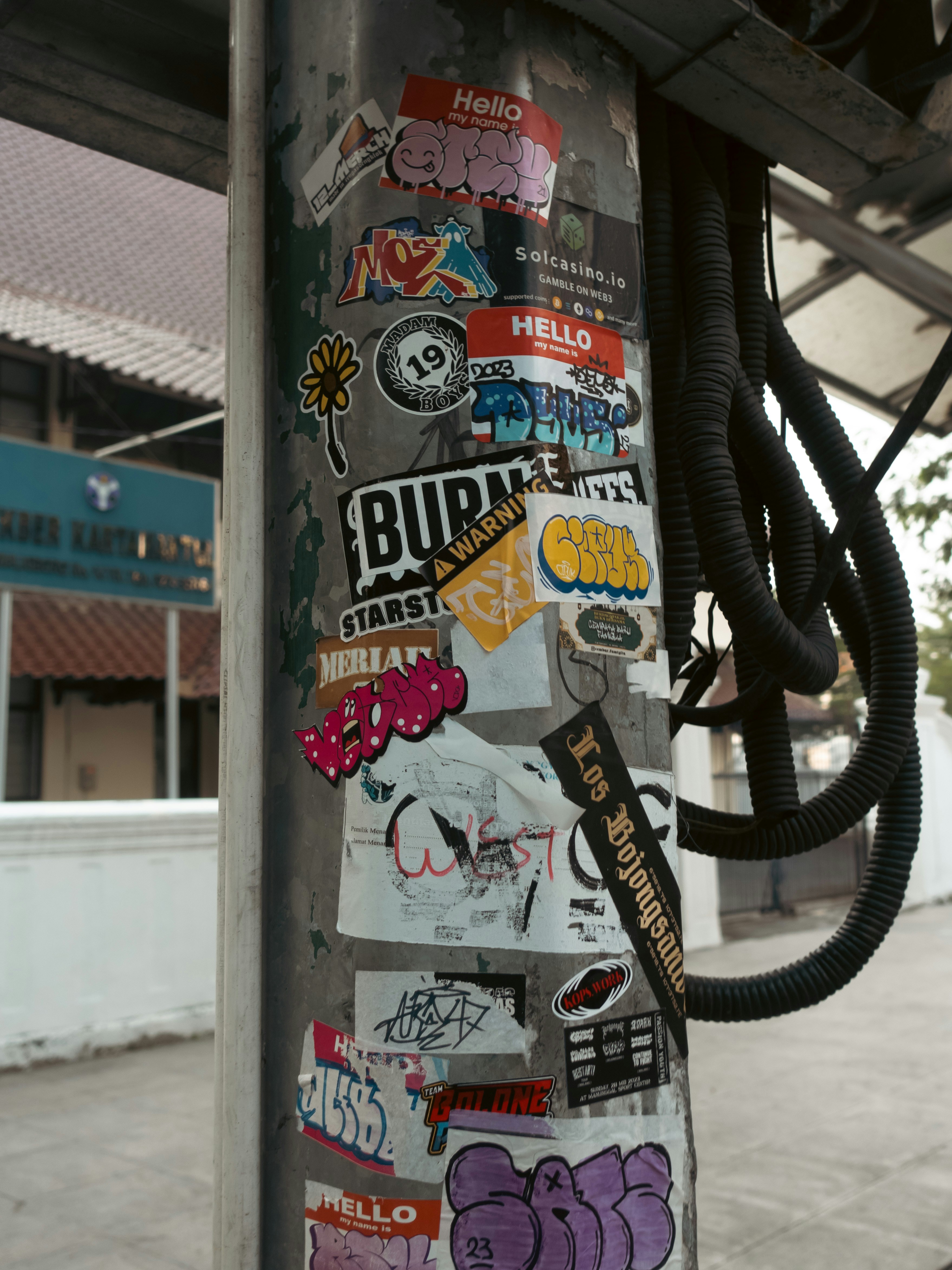 Stickered Pillar in Transit Light: A Colorful Urban Pole as Street Art