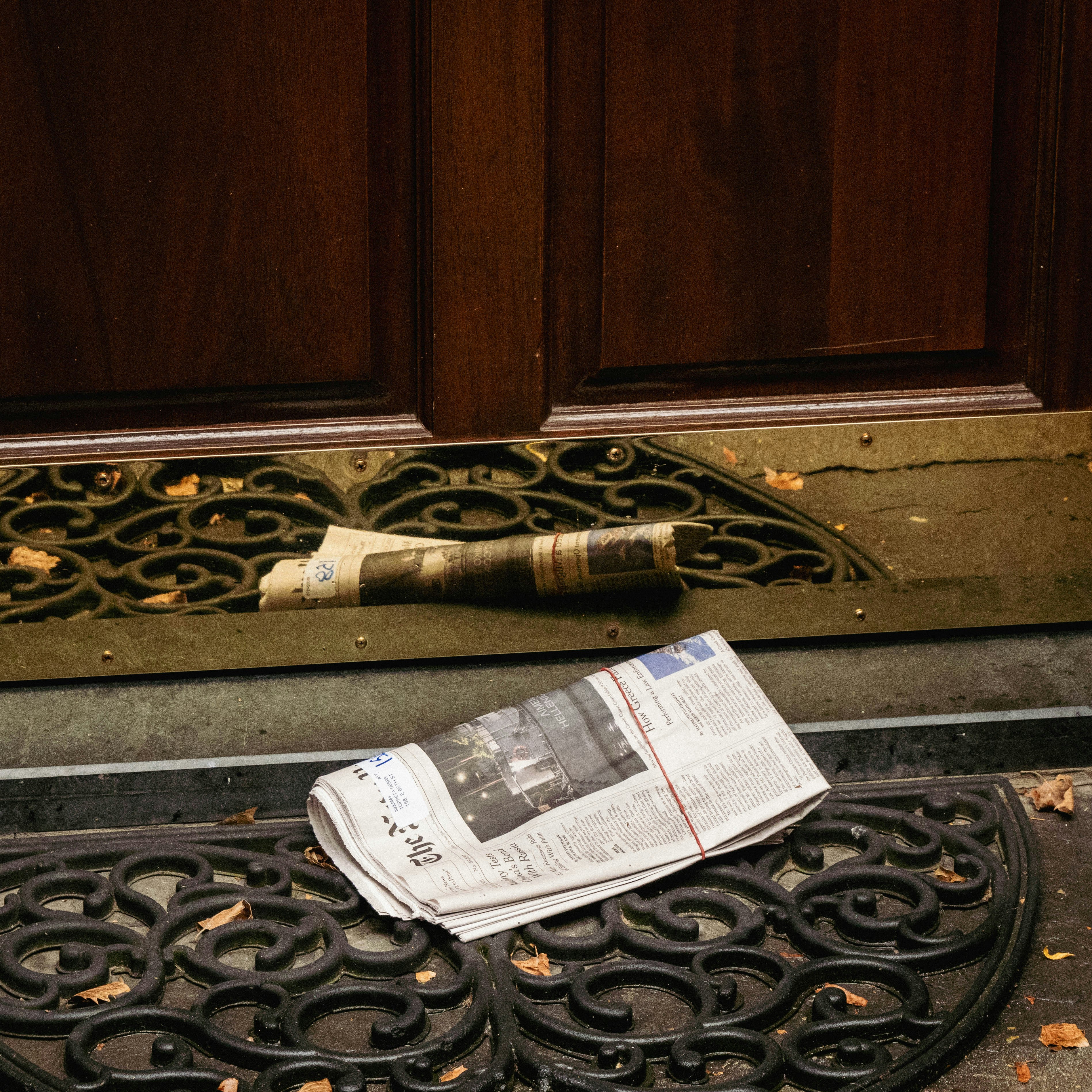 A newspaper laying on the ground next to a door photo – Free Newspaper ...