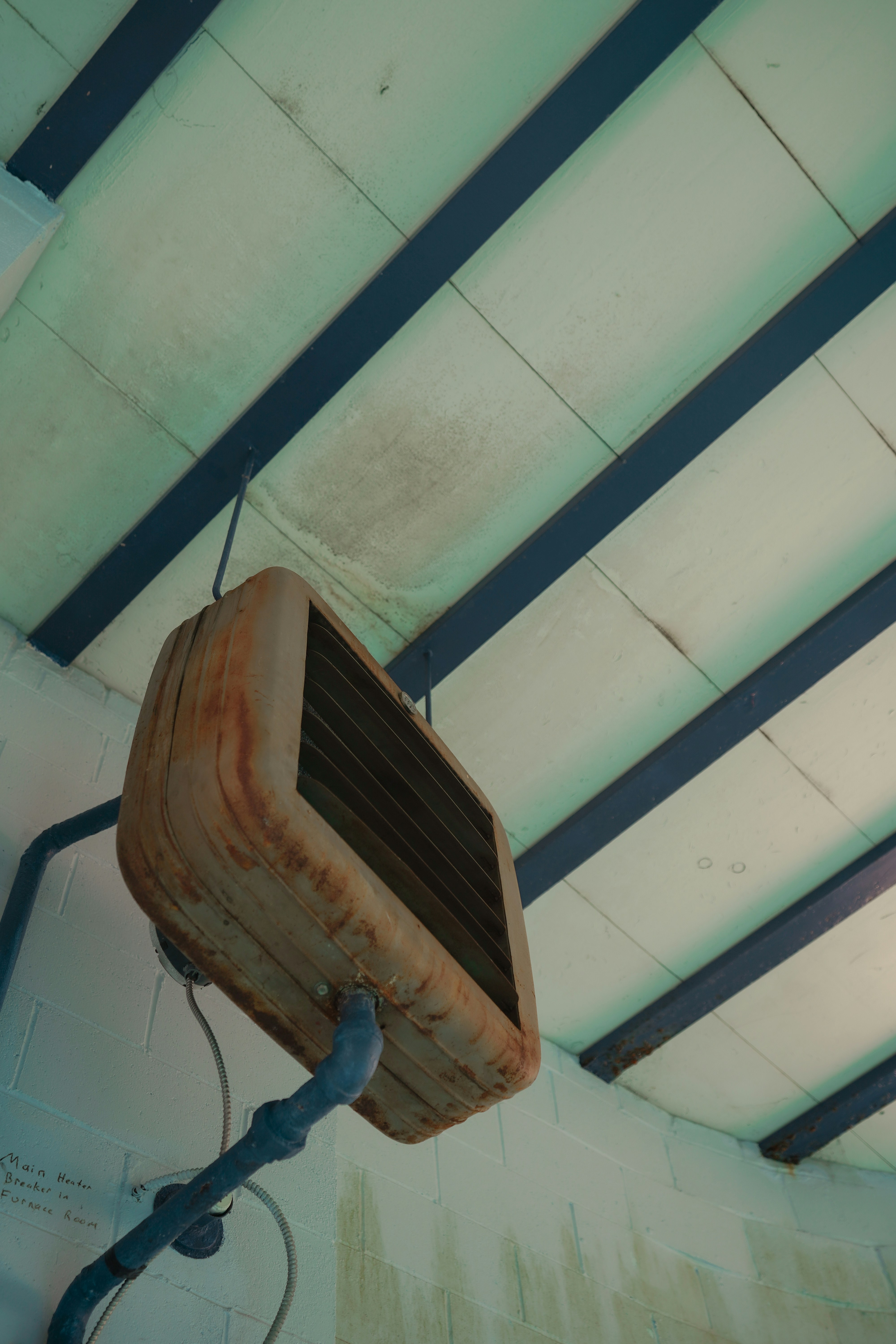 Rust-Rimmed Vent Under Teal Ceiling Beams