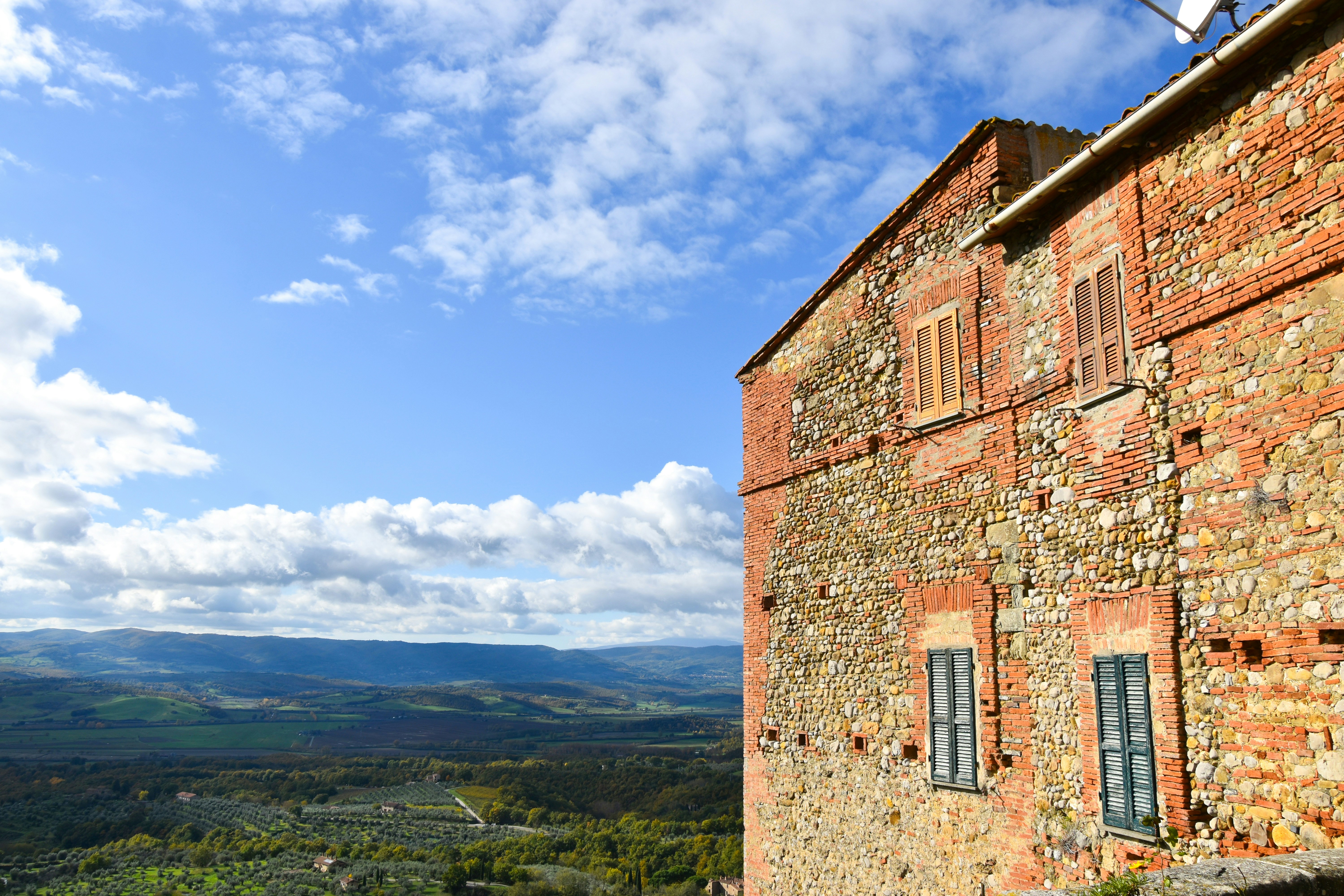 Old brick building overlooking a vast valley under a partly cloudy sky.