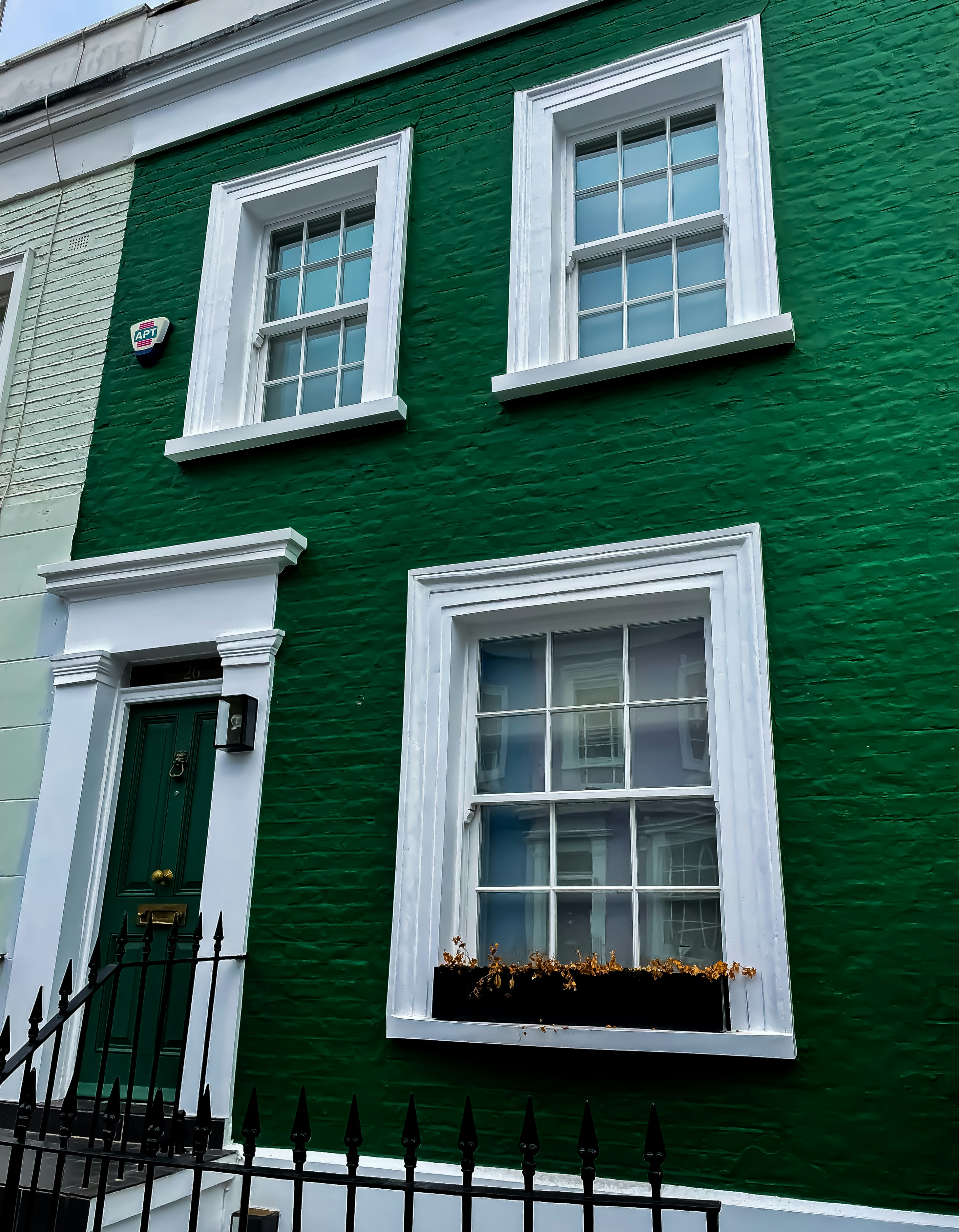 A green building with white windows and a black fence photo – Free Uk ...