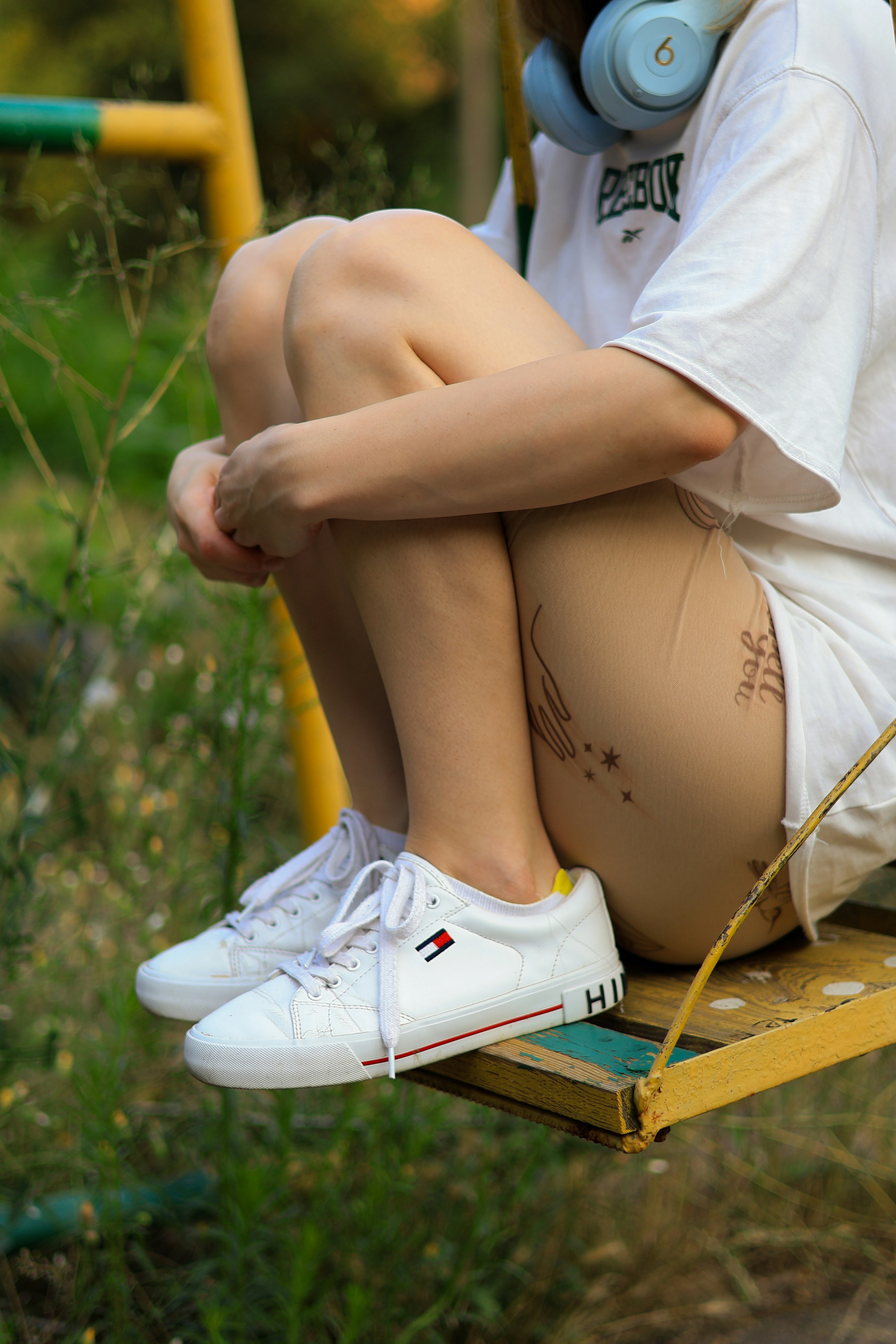 Muted Light, Blue Headphones: Tattooed Calm on a Swing