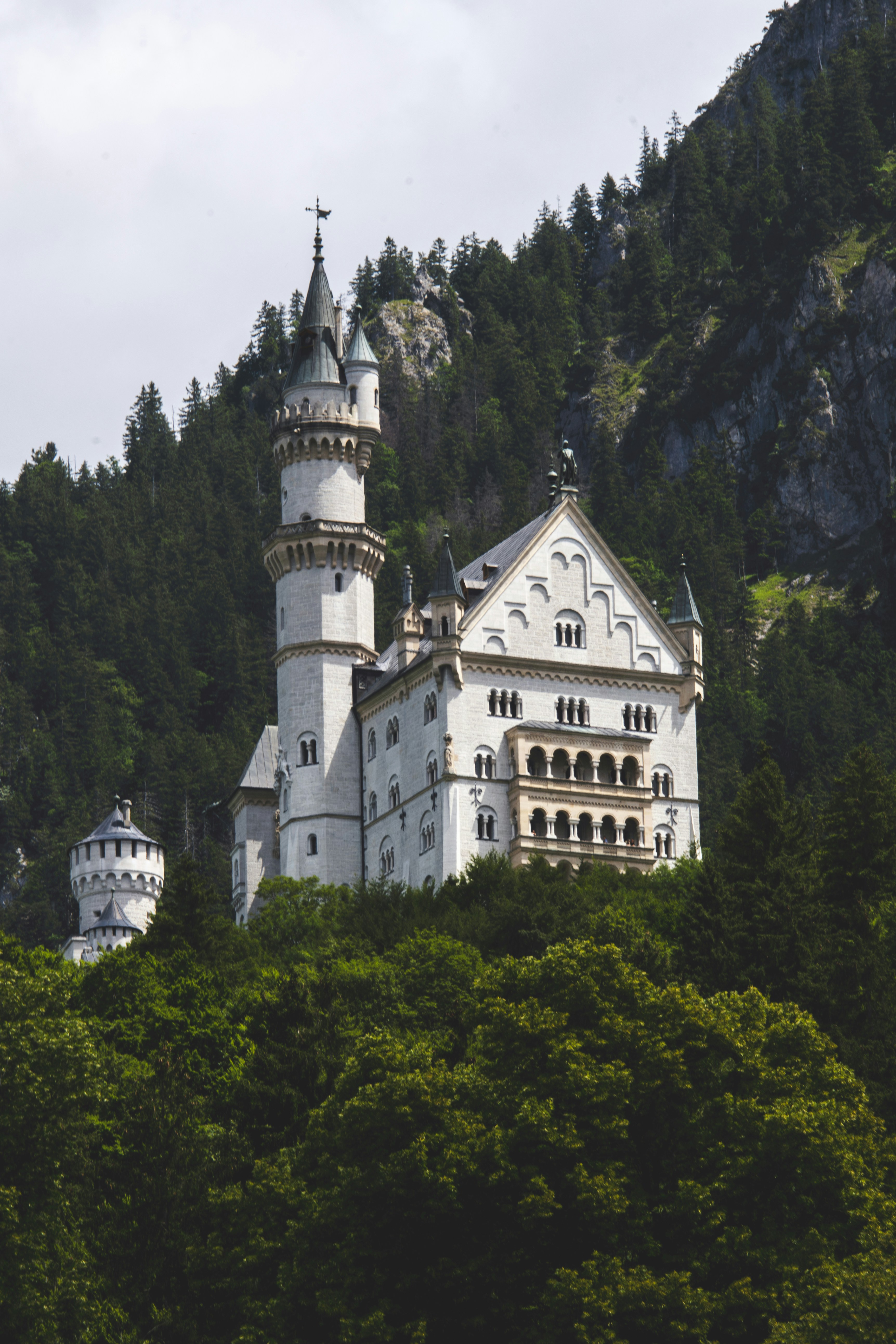 A large white castle sitting on top of a lush green hillside photo ...