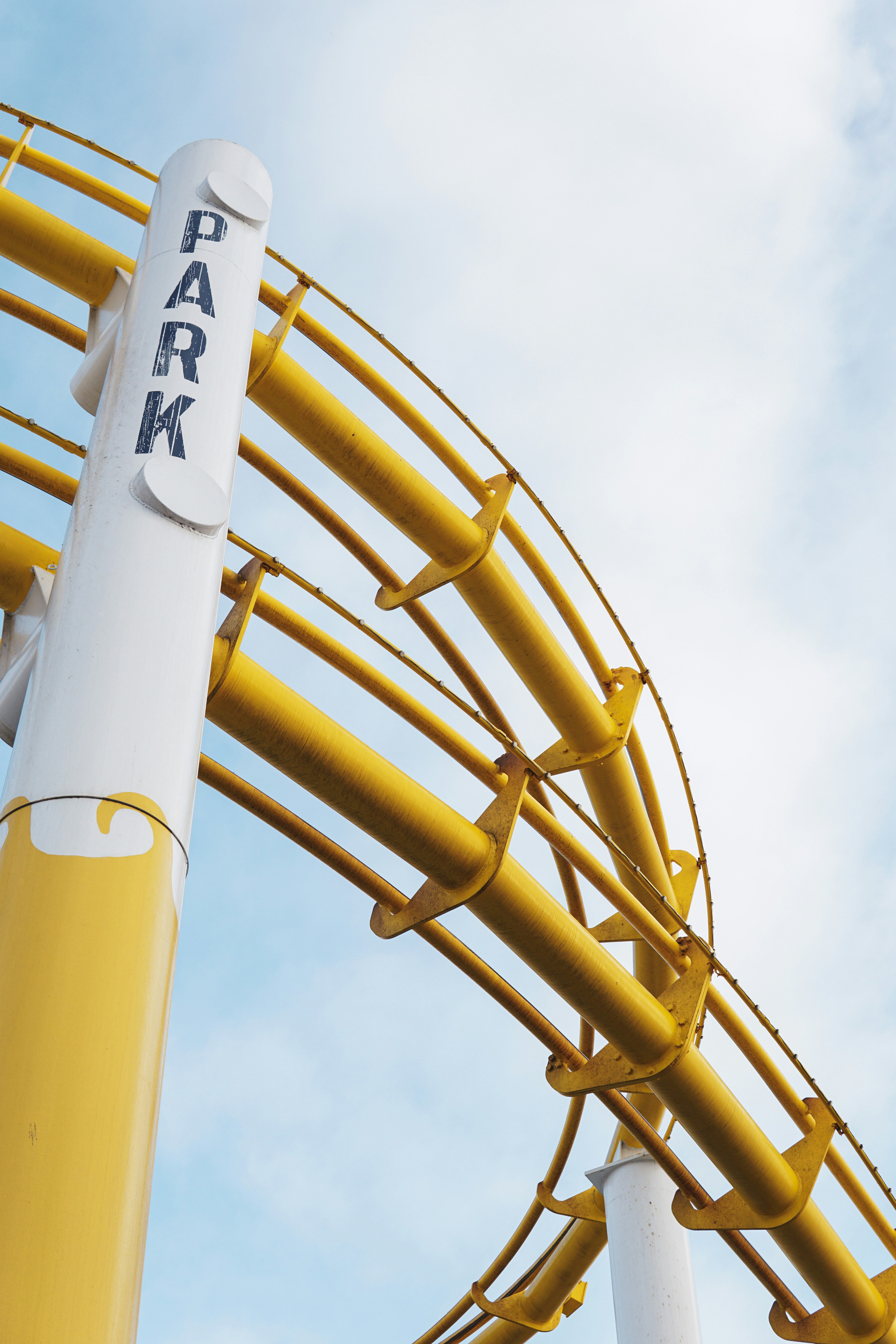 Sunlit Steel: A Close-Up of a Yellow Coaster's Bold Curve