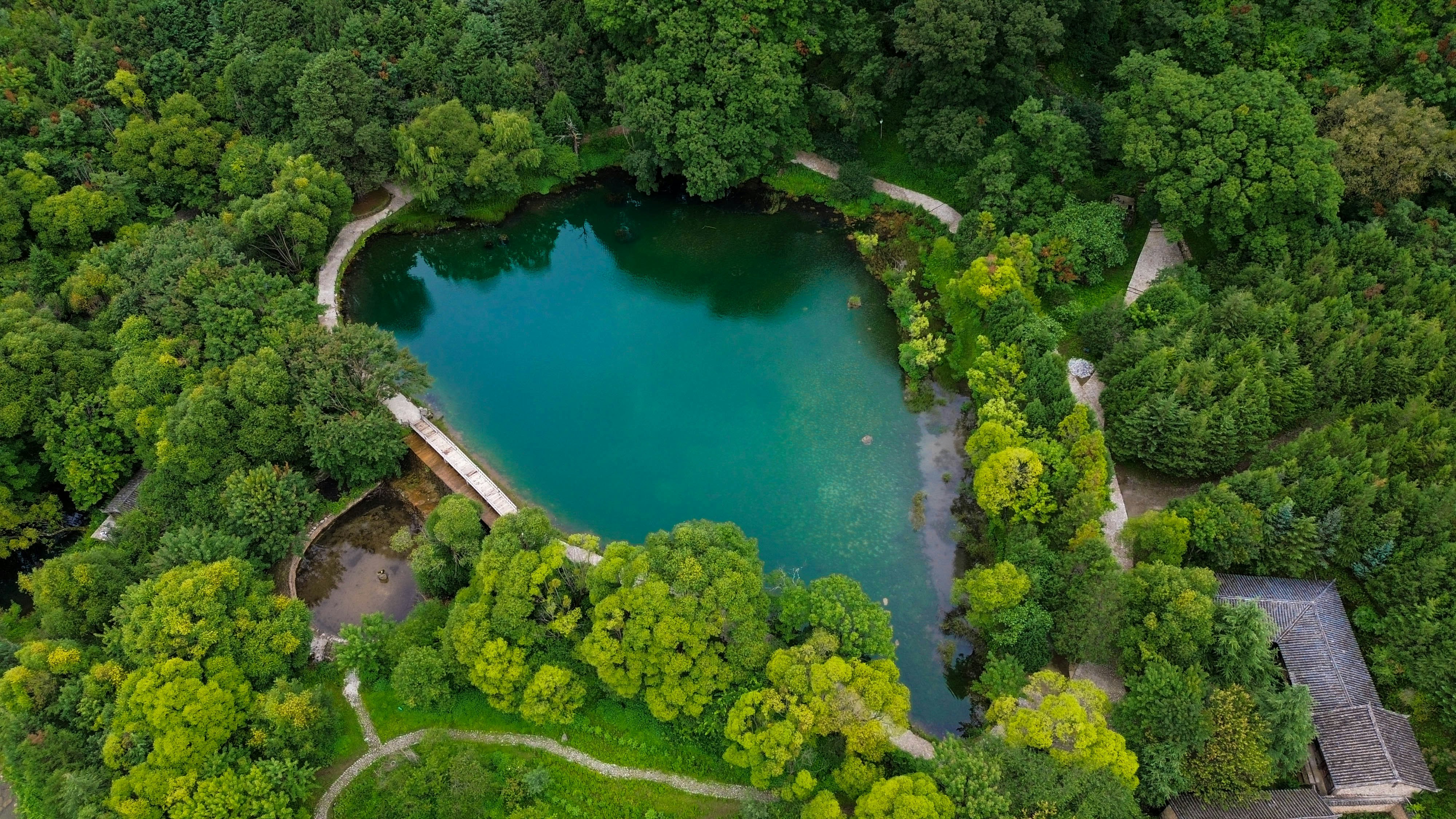 Aerial view of a heart-shaped lake surrounded by lush greenery and winding pathways.