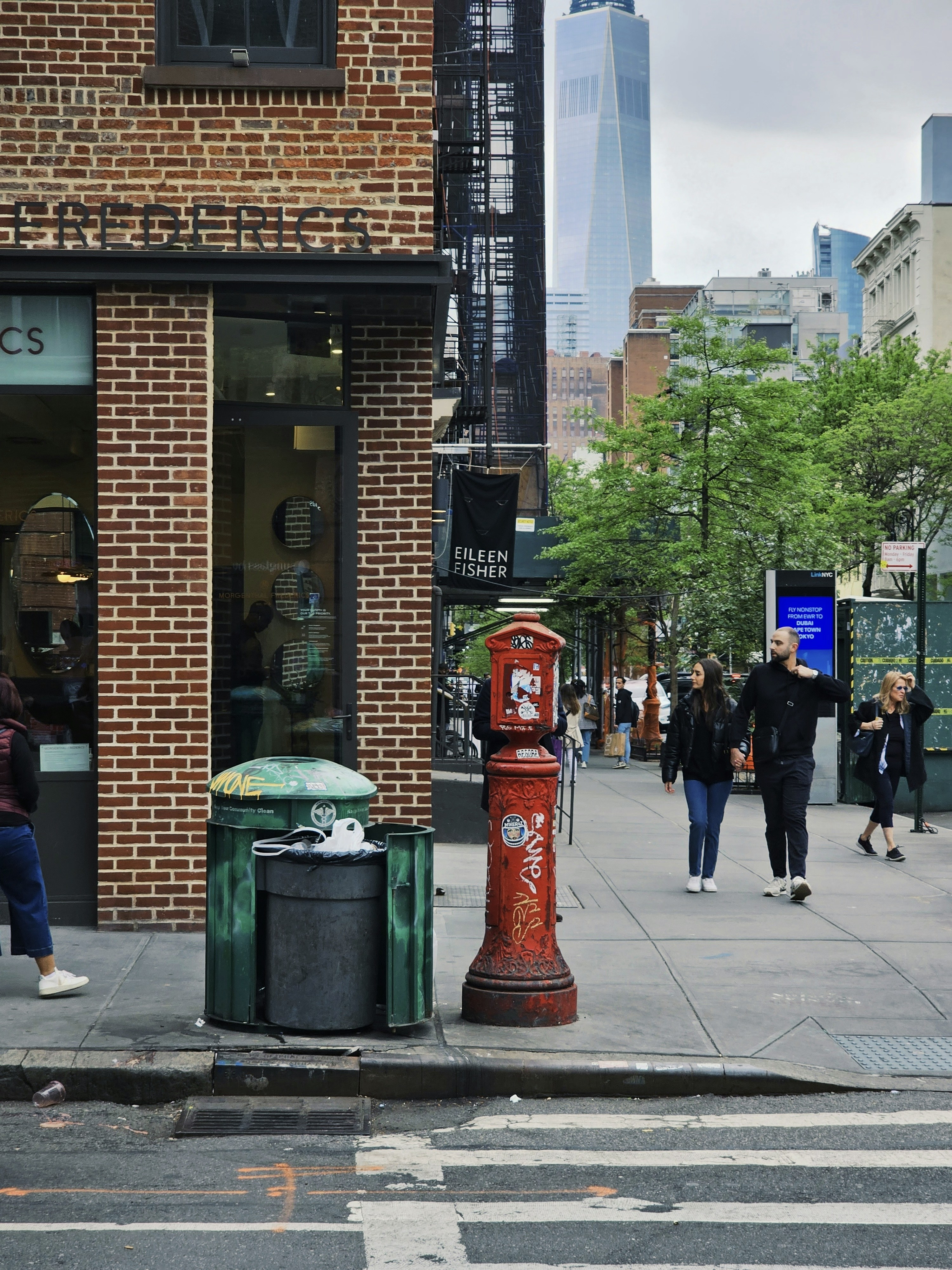 Urban Corner Echoes: Red Post, Brick Facades, and a Skyward Glass Spear
