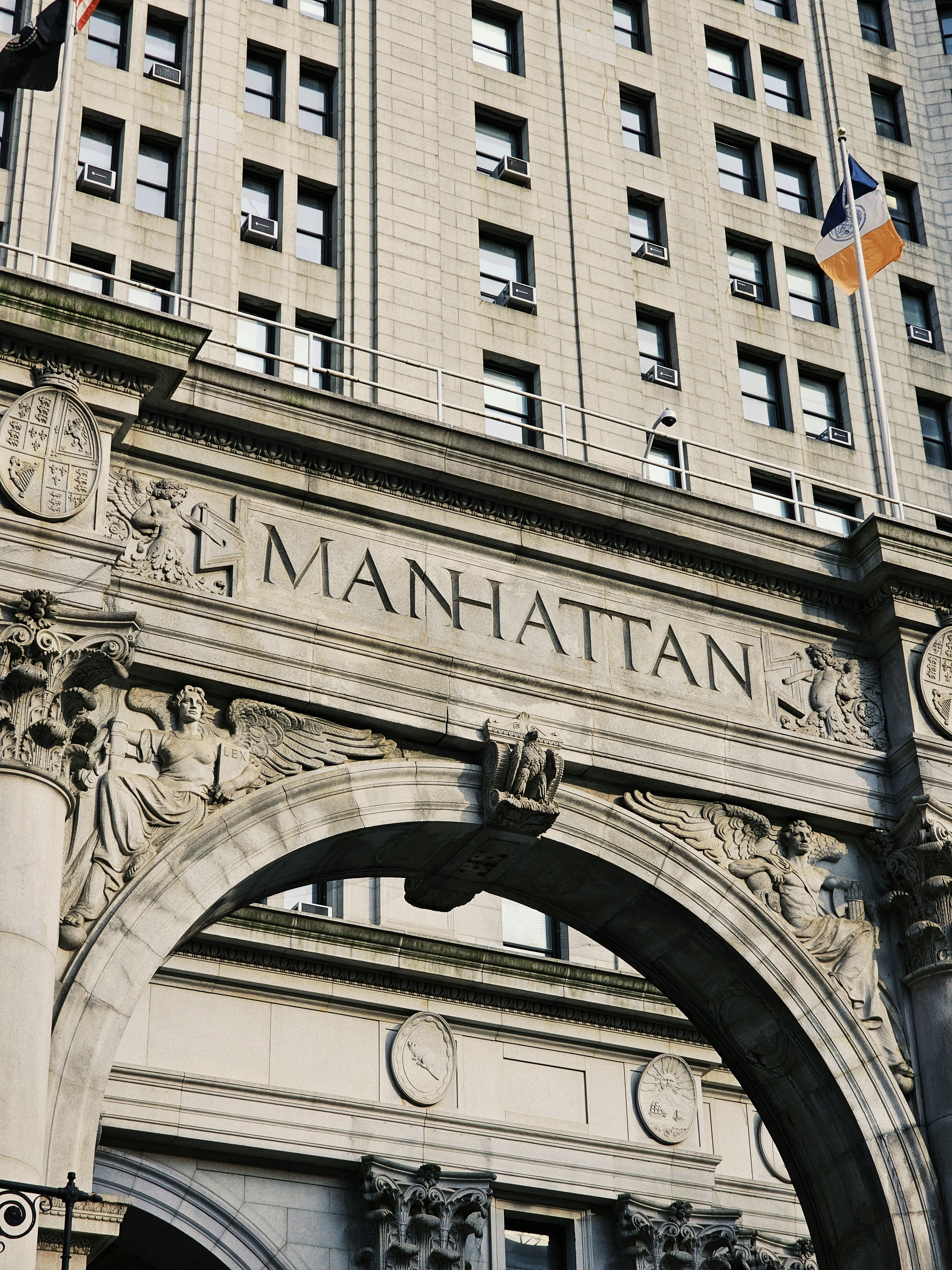 Manhattan Archway: Stone Carvings Framing a Skyscraper Facade