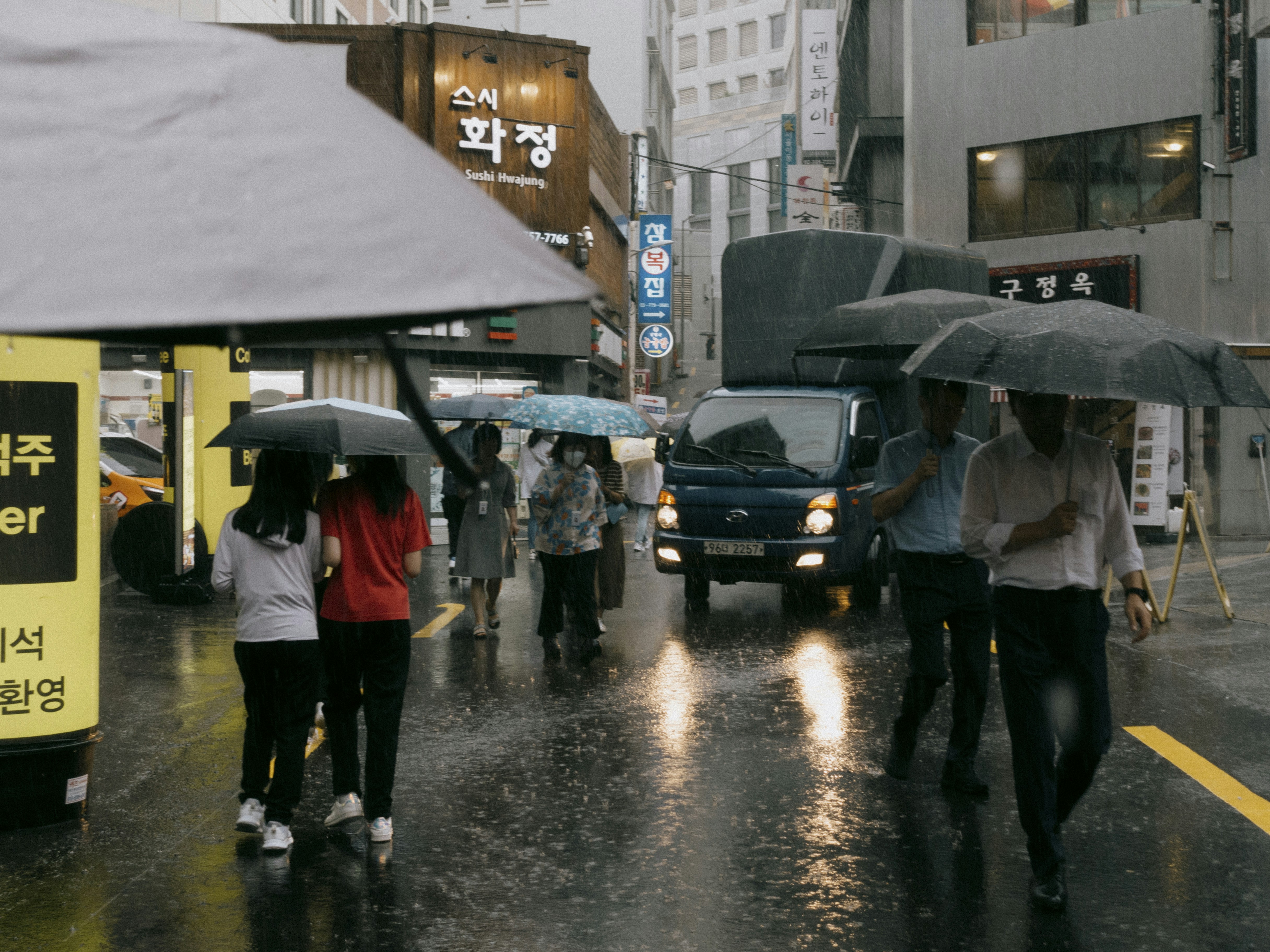 a group of people walking down a street holding umbrellas