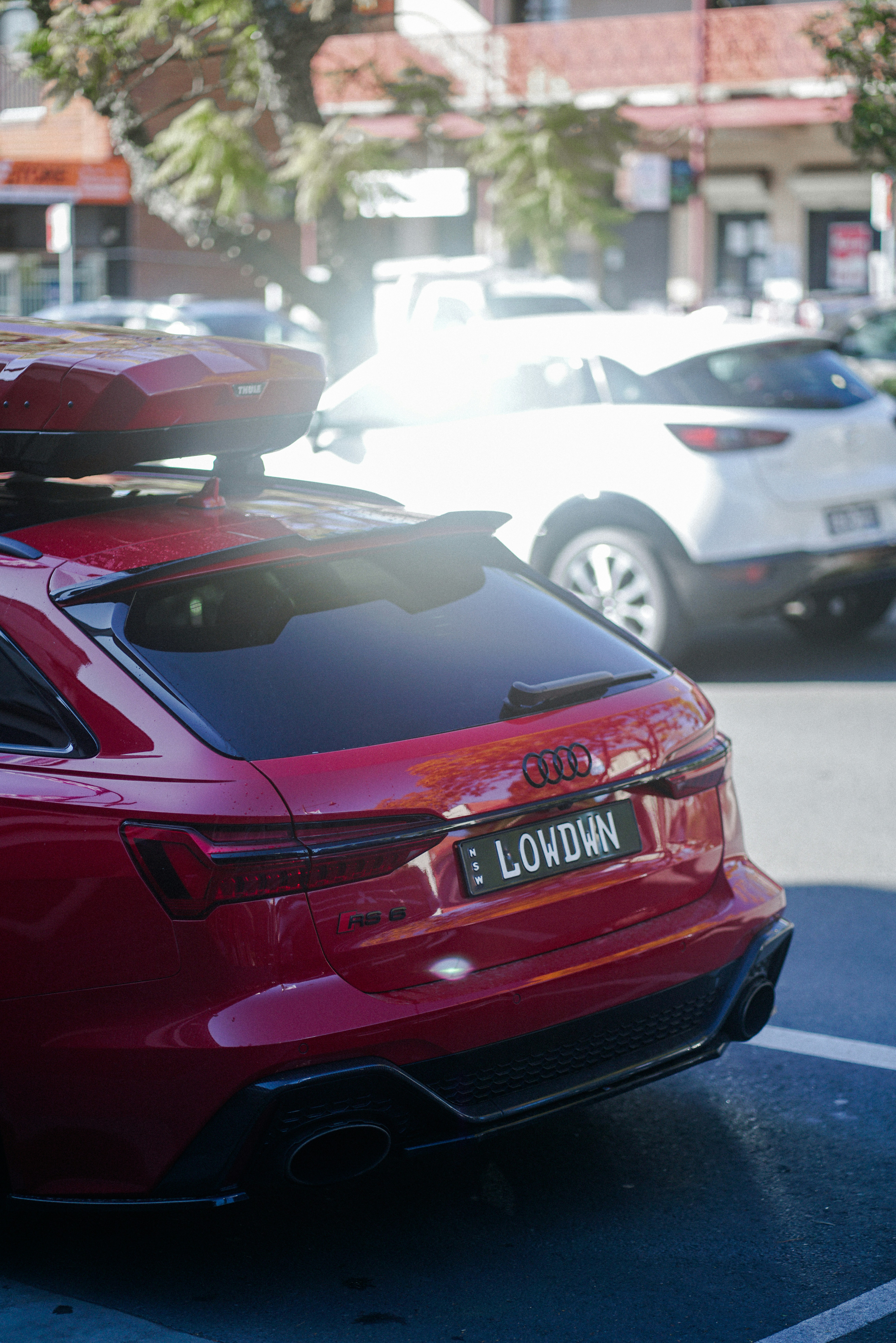 Rear View of a Red Audi with License Plate Reading 'LOWDWN' in a City Parking Lot