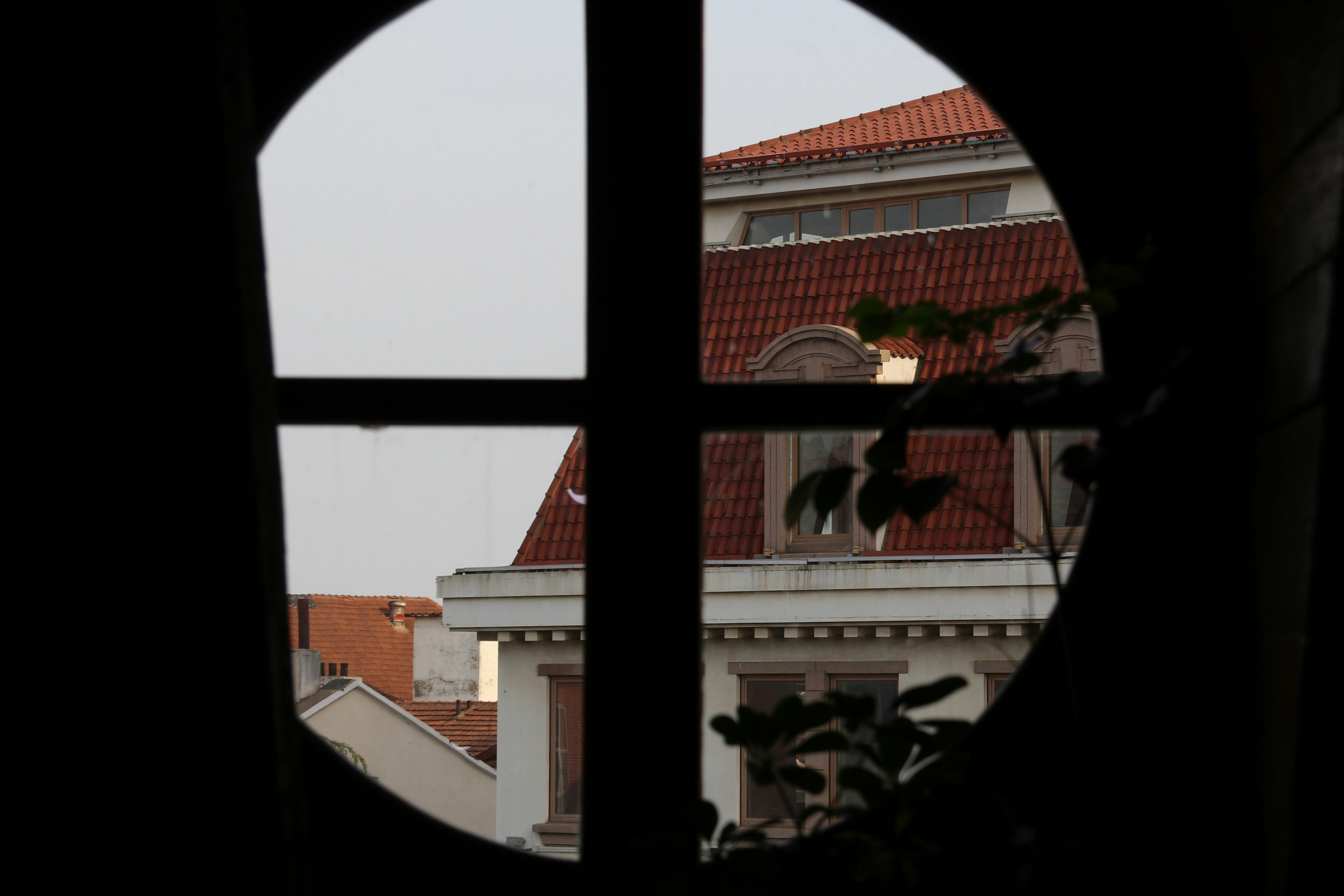 Circle of View: Red Rooftops Framed by a Shadowed Window