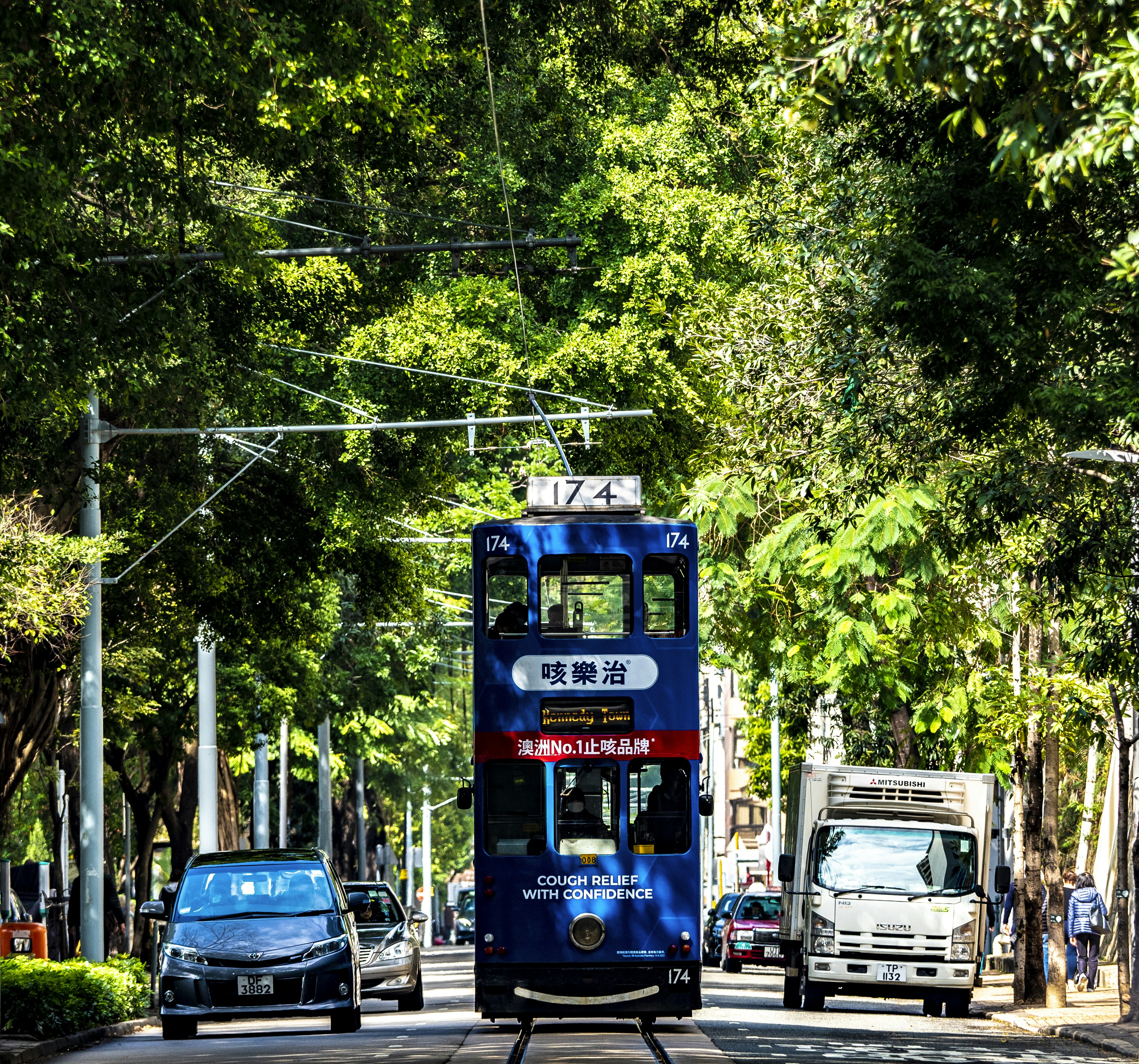 Azure Tram Through a Sunlit Green Corridor