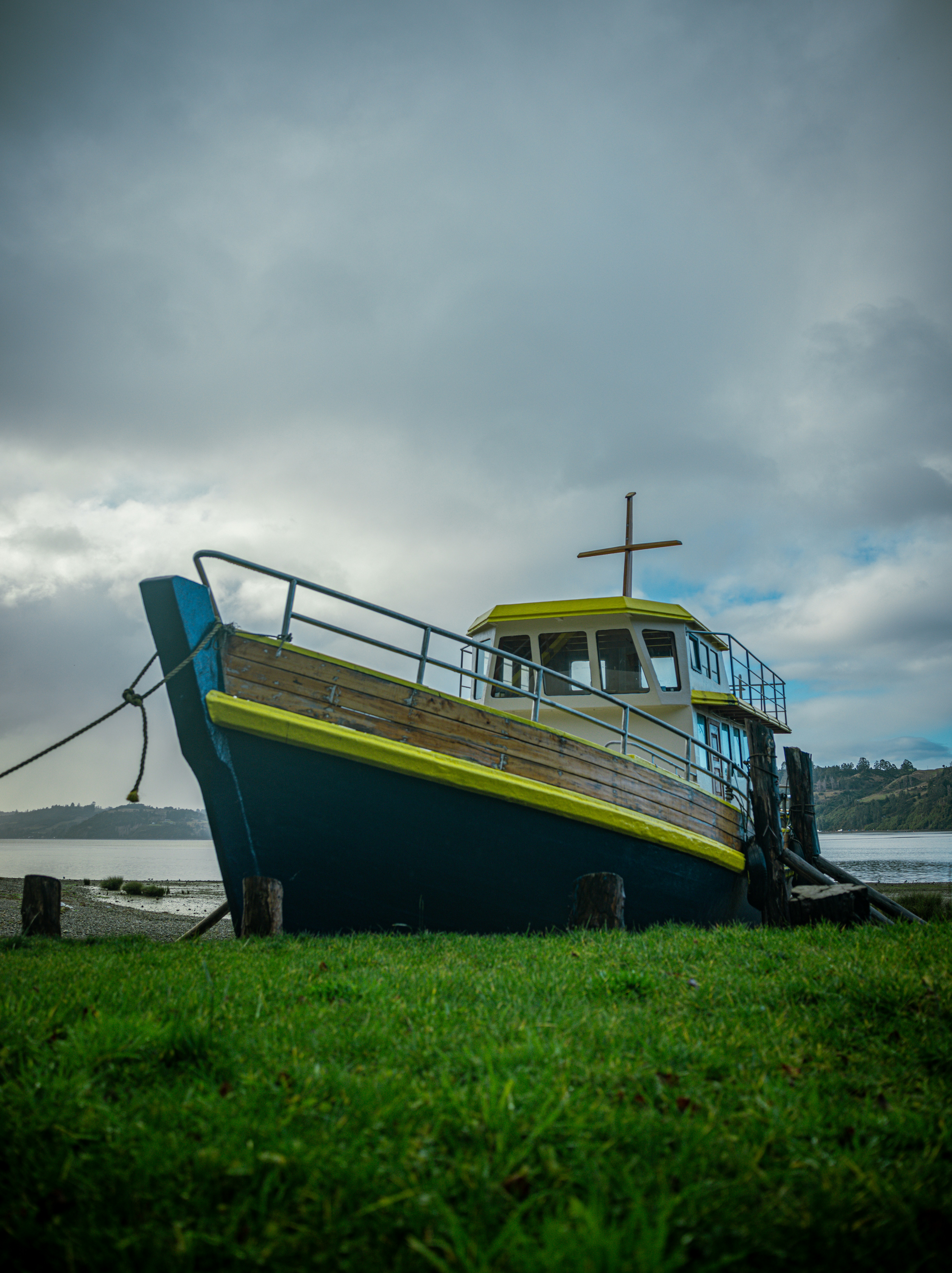 Beached Cabin Boat at the Mooring: A Blue-Yellow Vessel on a Moody Shore