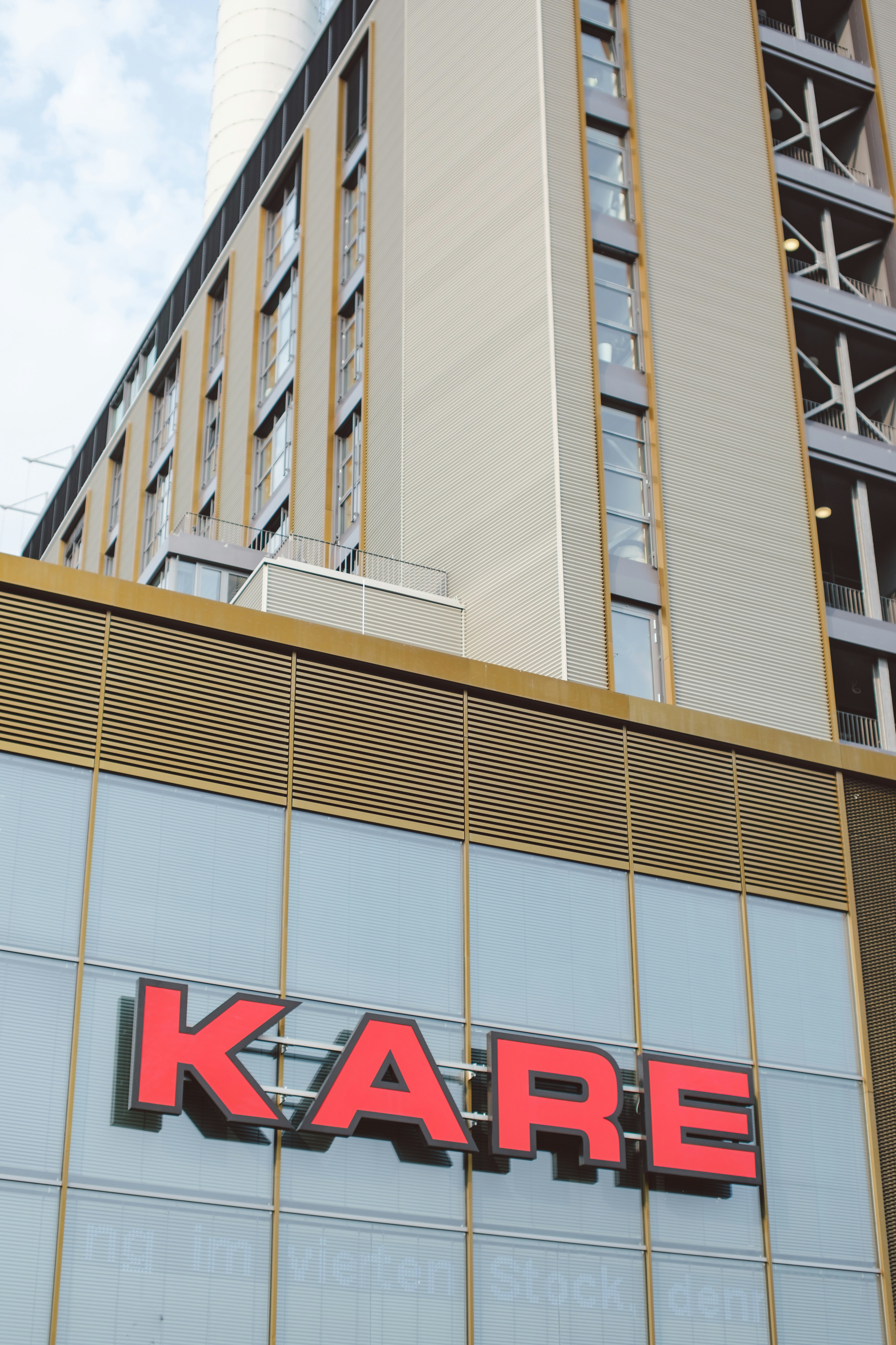 Crimson KARE Sign Anchors a Stripped Glass Facade
