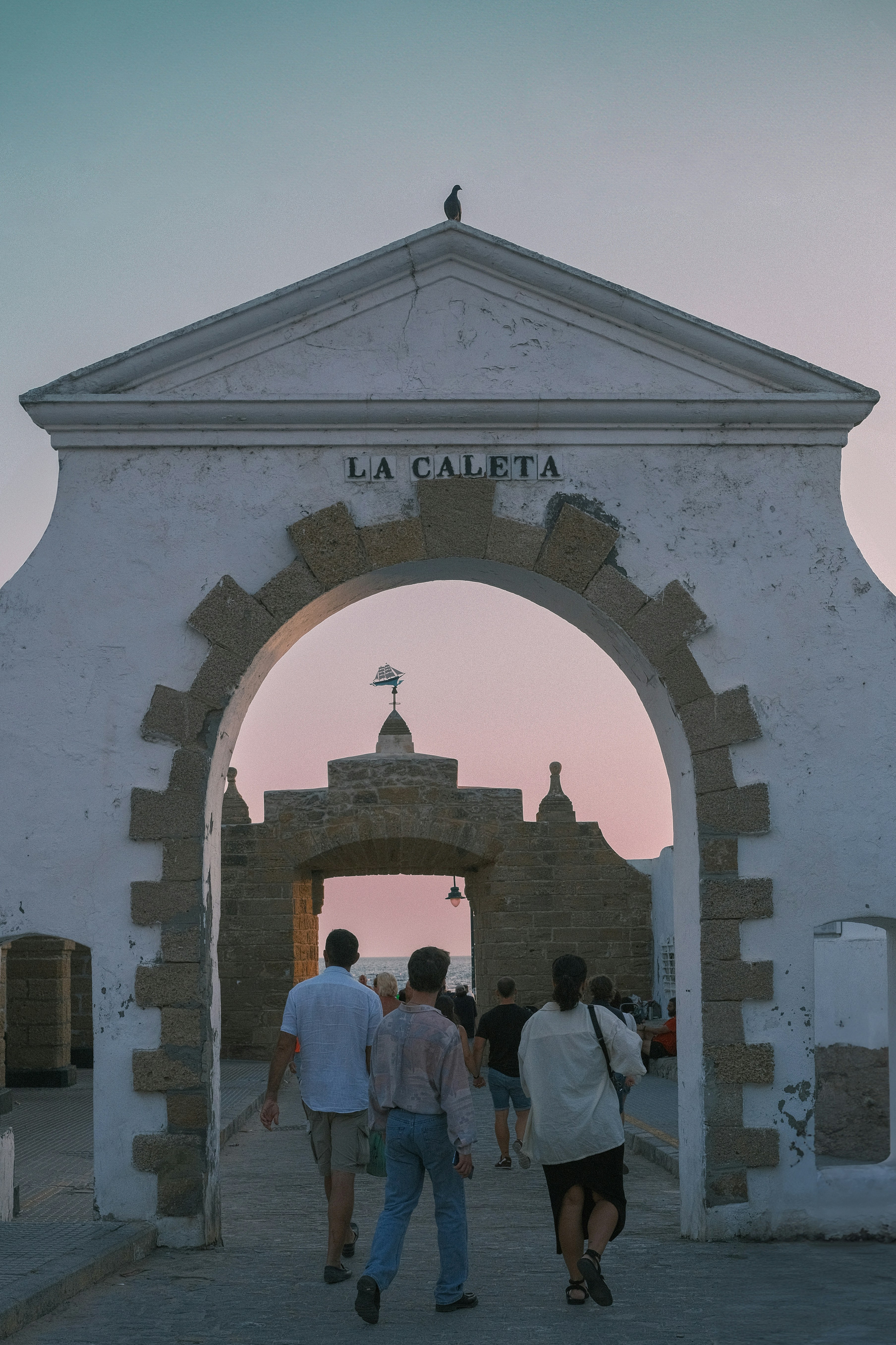 A group of people walking through a stone archway photo – Free Spain ...