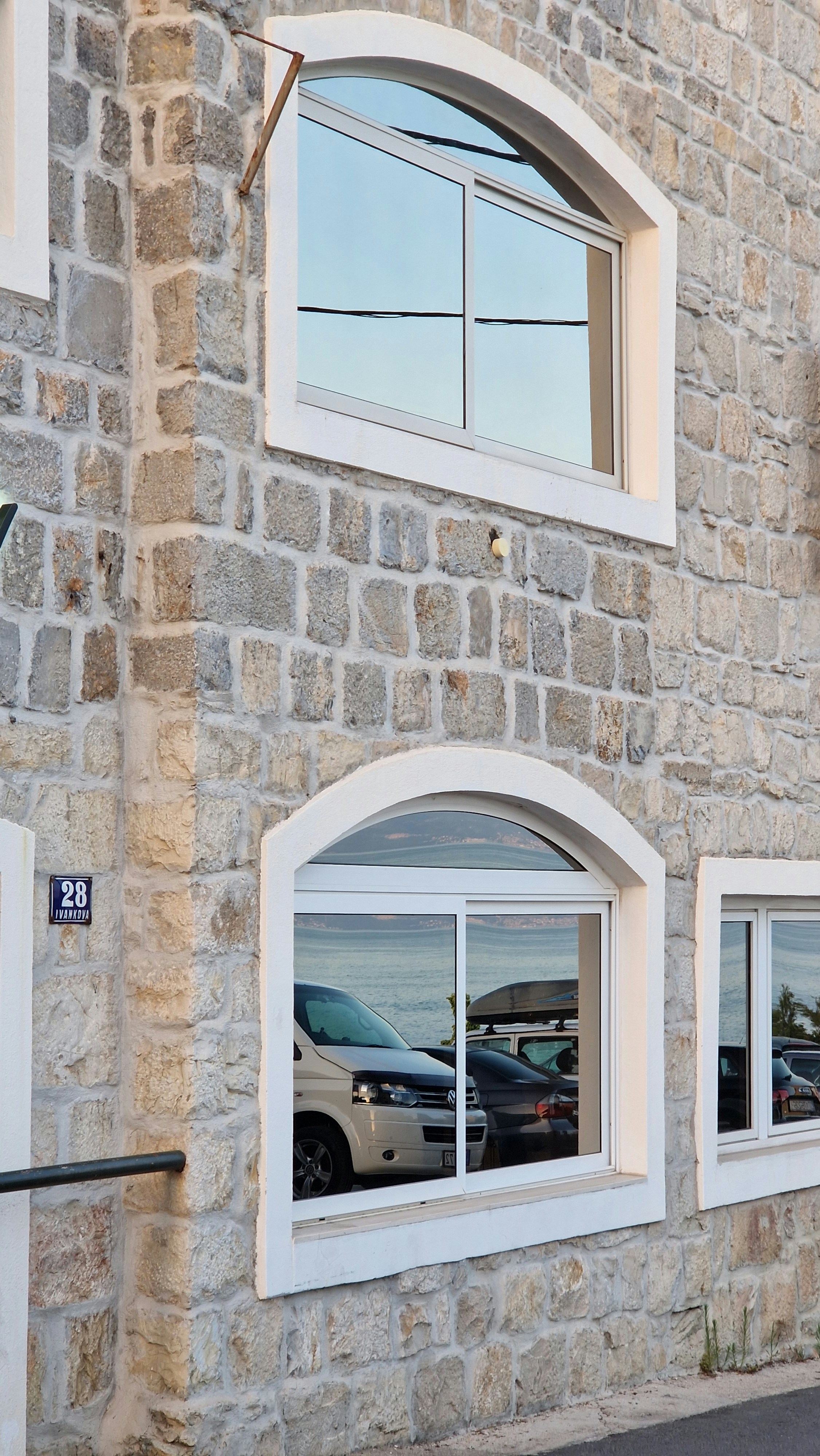 Stone-Arched Windows by the Sea: Reflections on a Coastal Facade