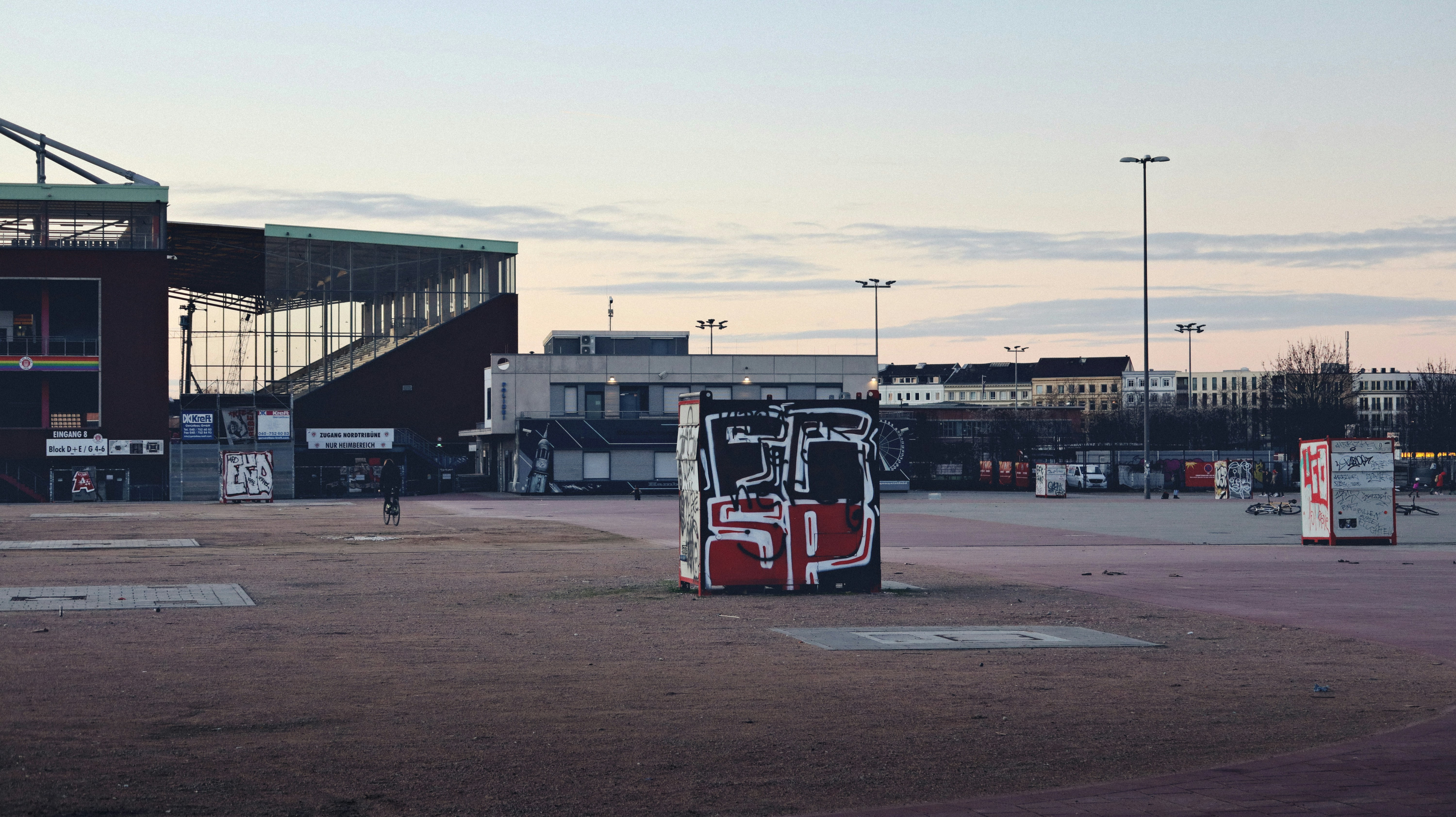 Graffiti Cube Anchoring a Quiet Stadium Lot at Dusk