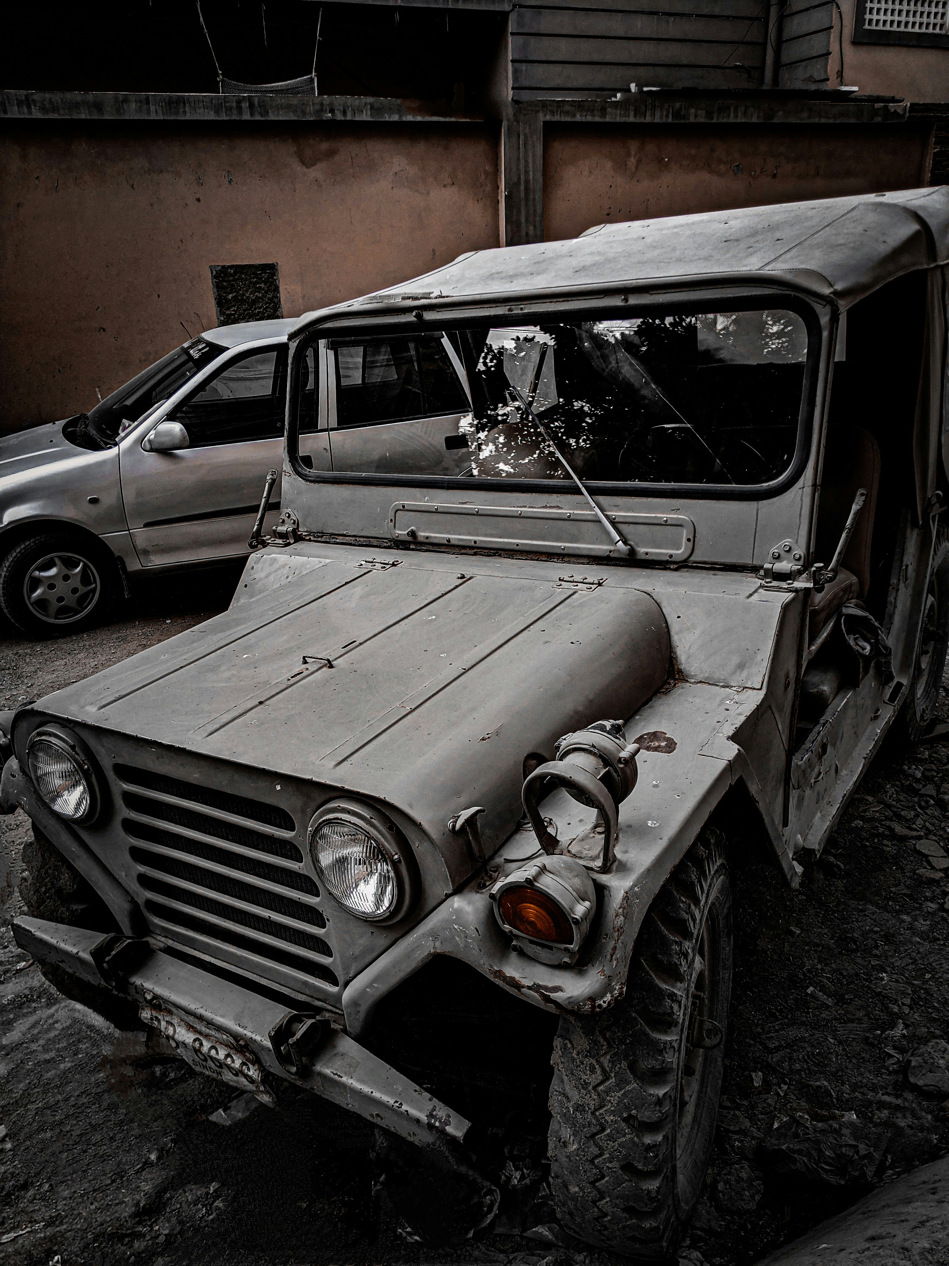 Weathered Frontline: A Rugged Jeep Guarding a Dim Yard