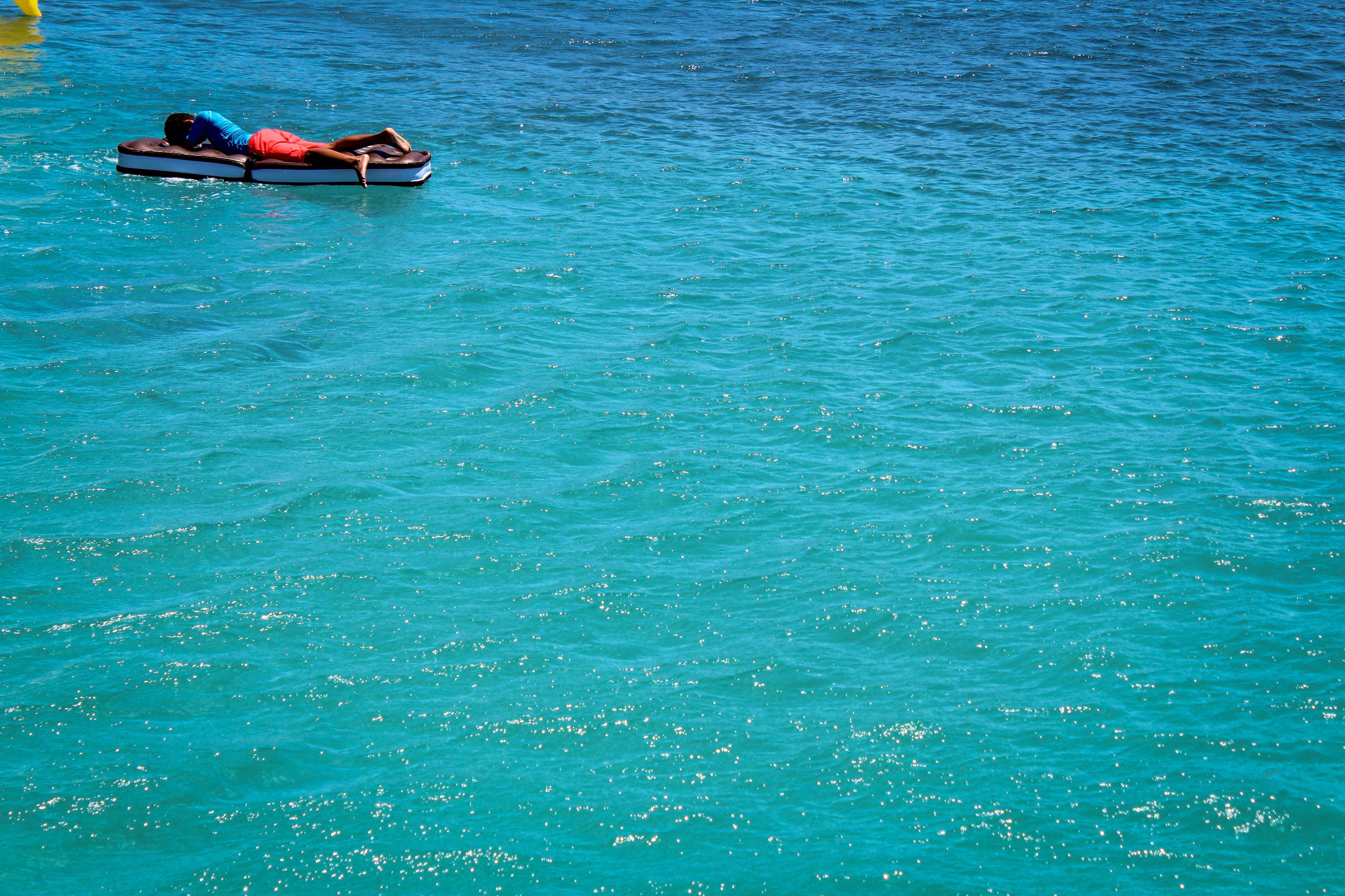 A person laying on a raft in the middle of a body of water photo – Free ...