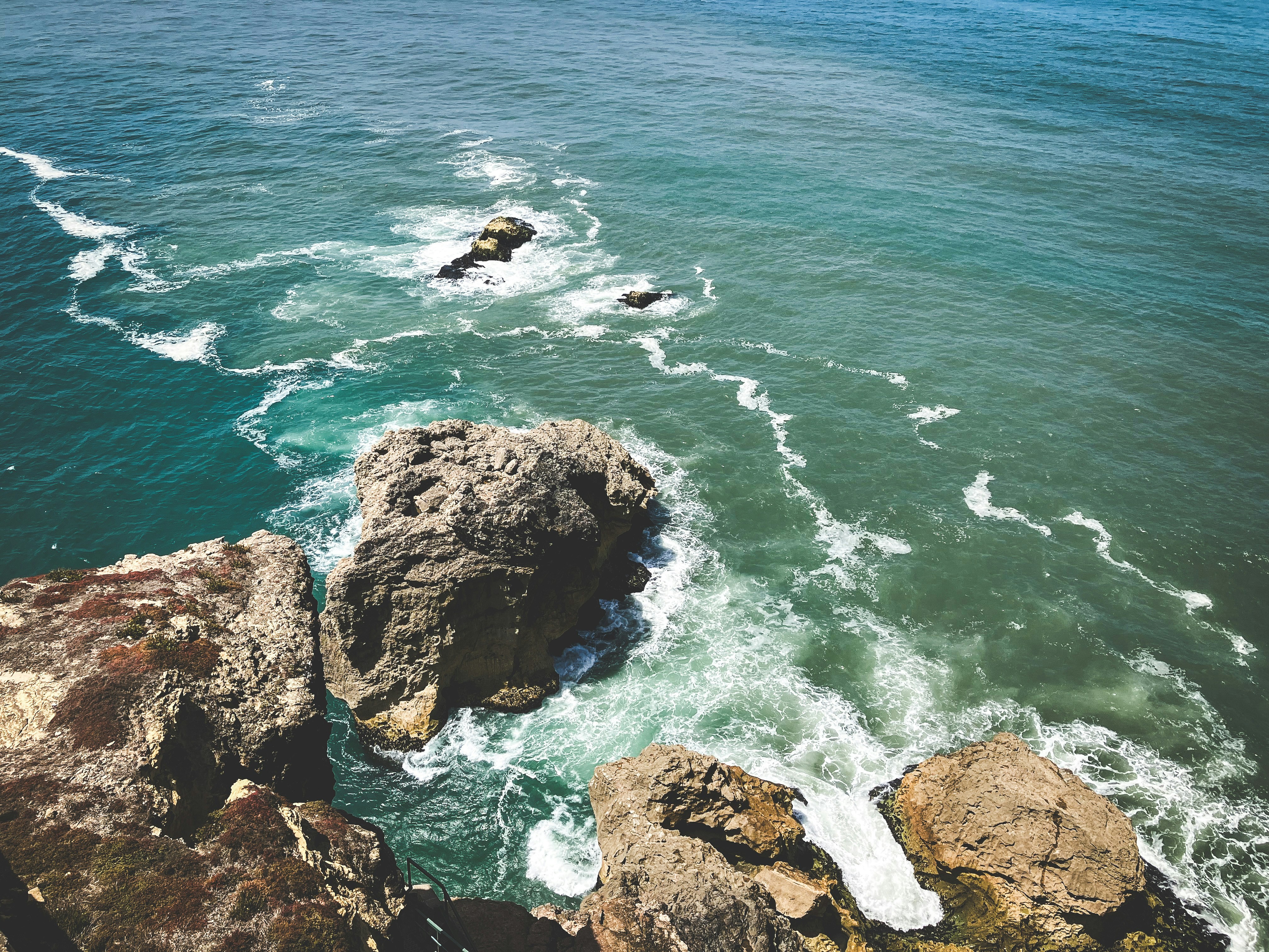 A body of water surrounded by rocks near a shore photo – Free Sea Image ...