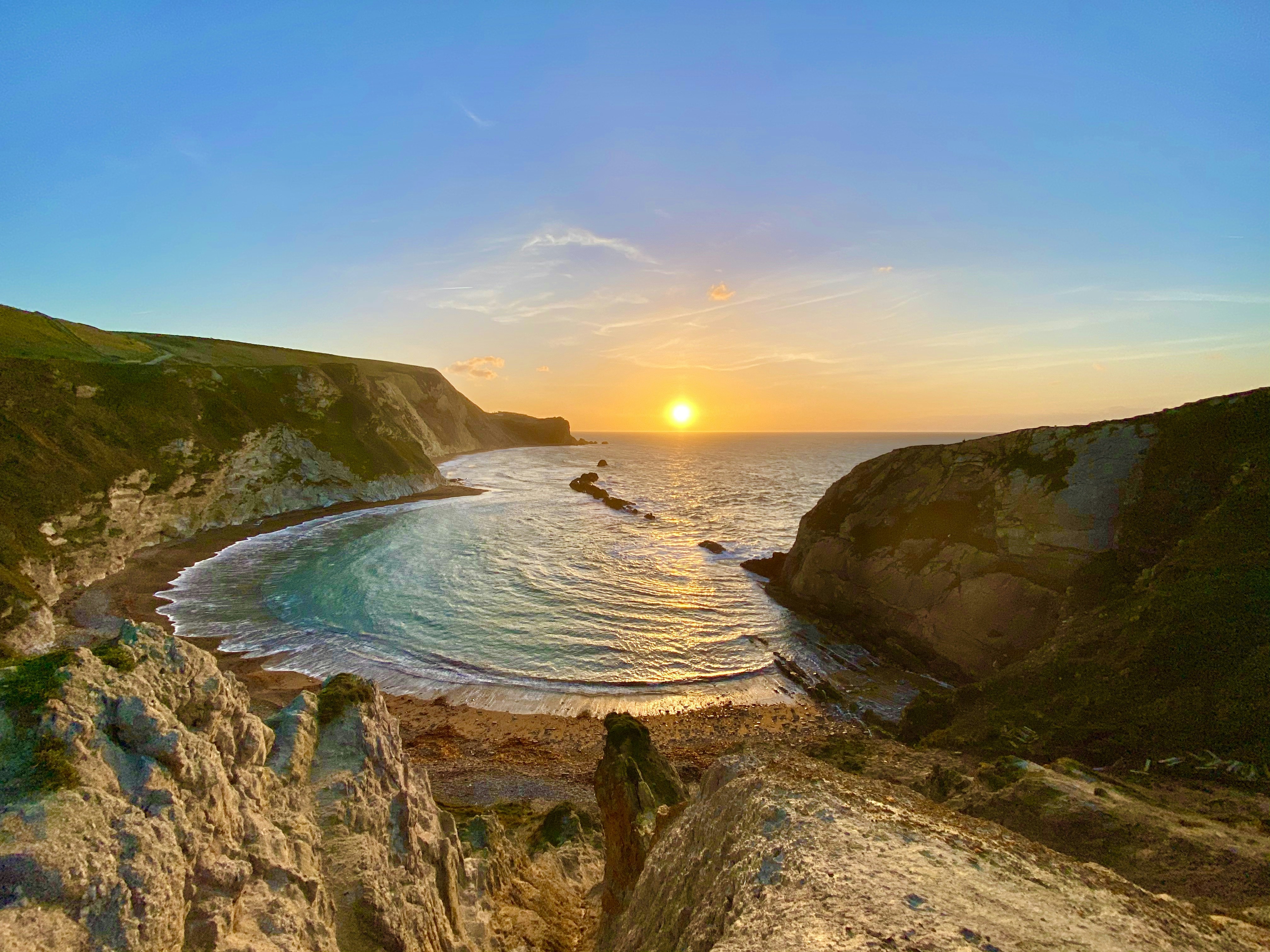 Sunlit Split: Cliff-Framed Cove at Dusk