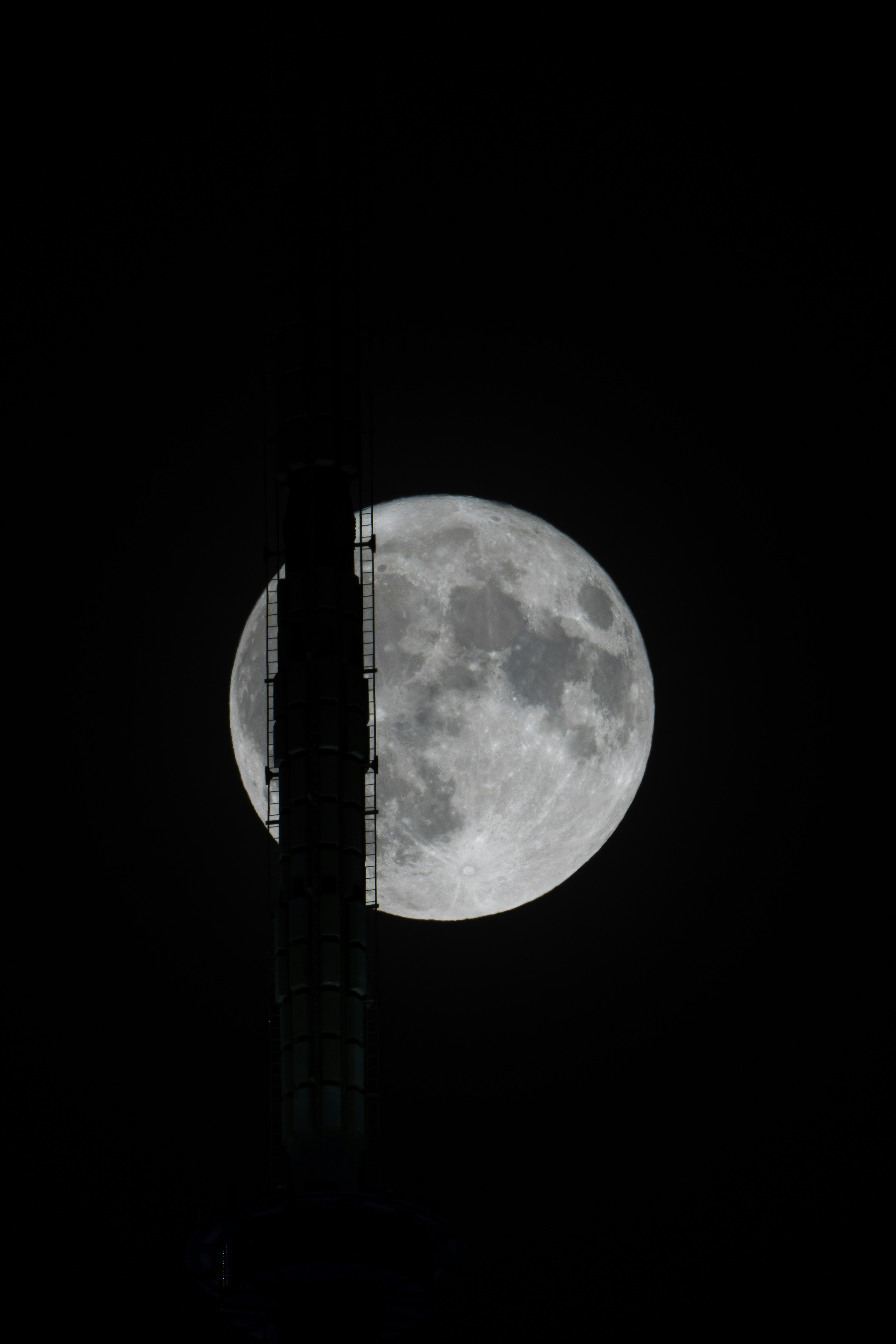 Lunar Silhouette: The Moon Framed by a Tower Mast