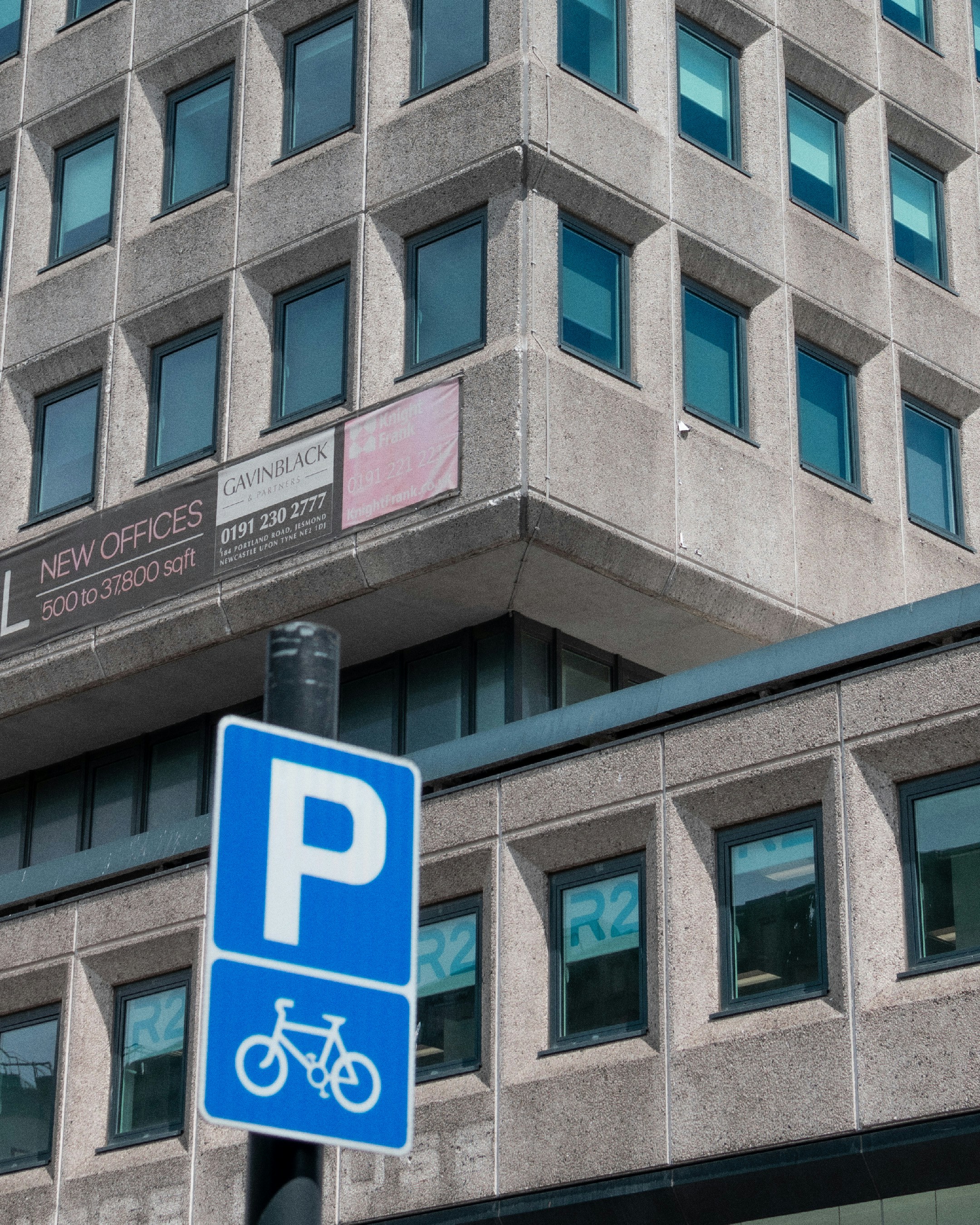A blue parking sign sitting in front of a tall building photo – Free ...
