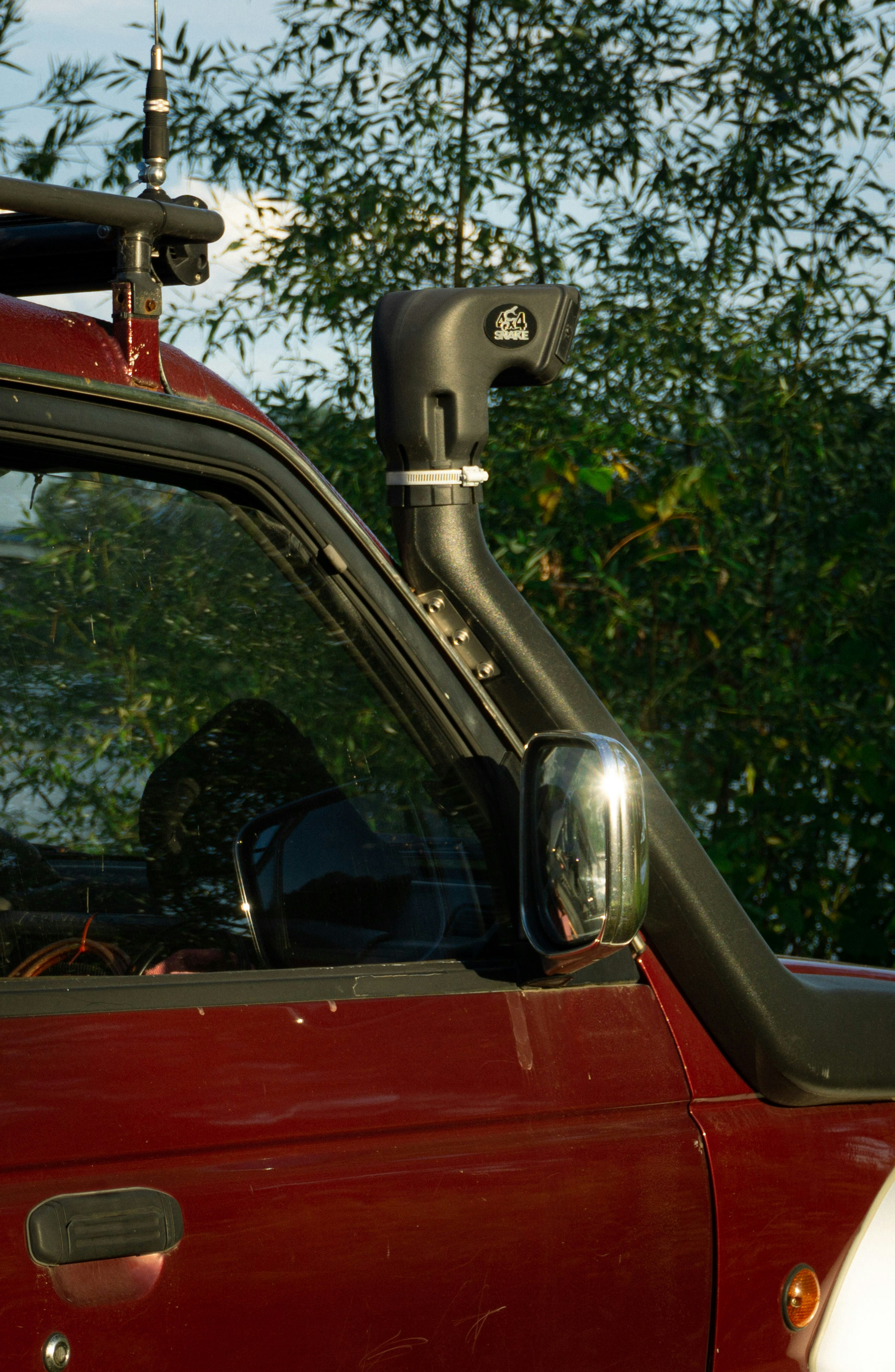 Snorkel Sentinel: A Red Off-Road Rig Framed by Green Canopy