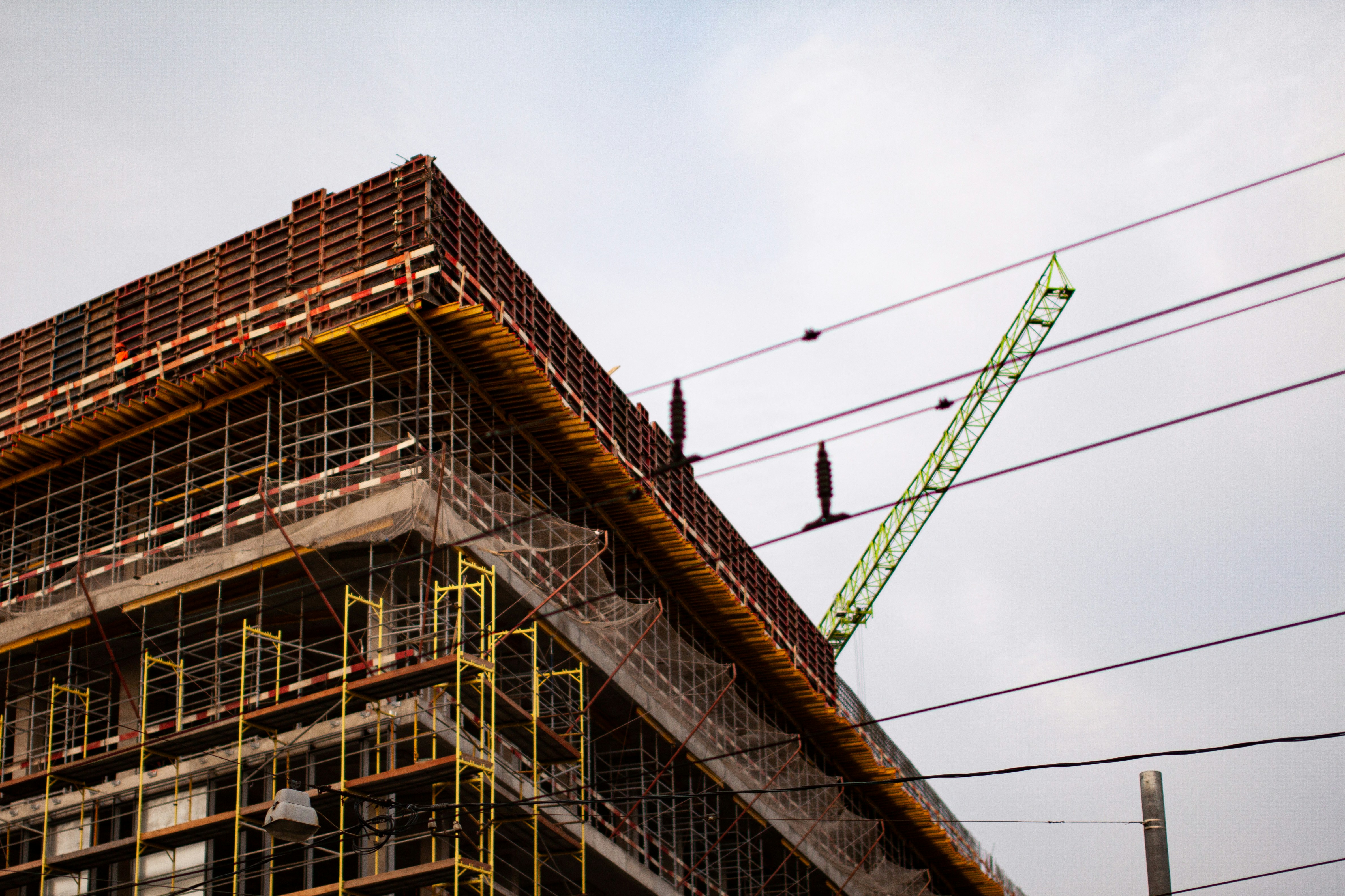 A crane is on top of a building under construction photo – Free ...