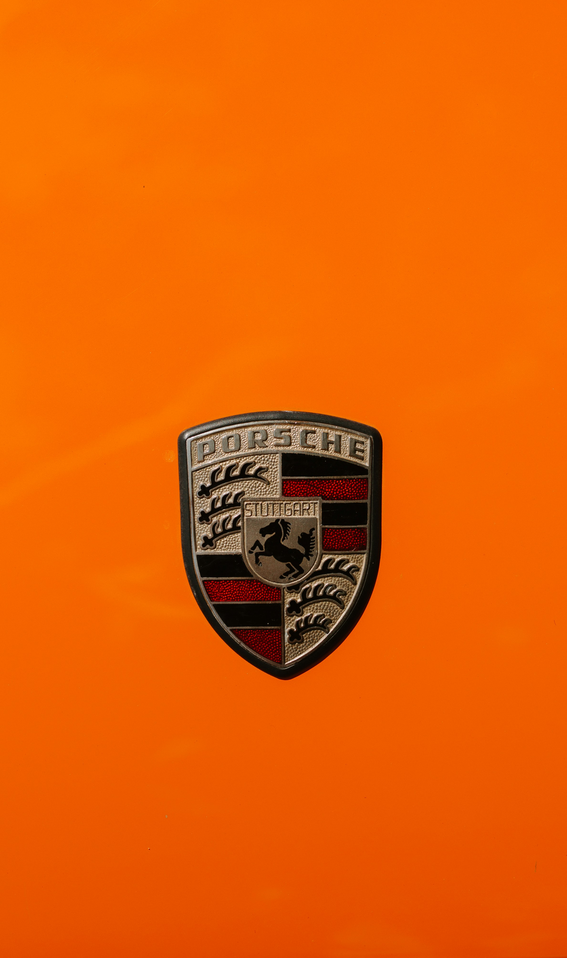 Emblem in Neon Orange: Porsche Crest Centered on a Vivid Car Surface