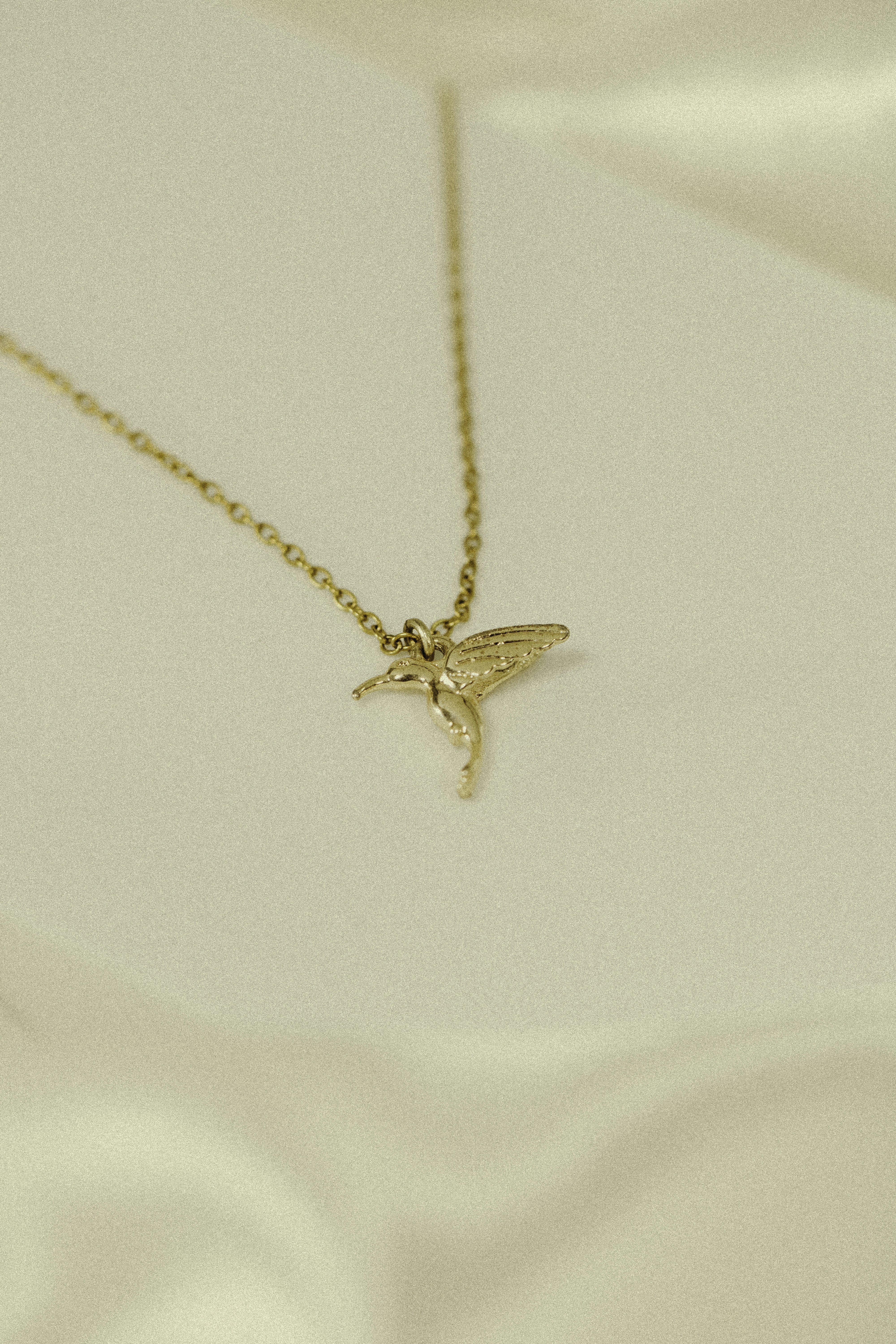 Pendant in Focus: Delicate Hummingbird Charm Resting on a Soft Canvas