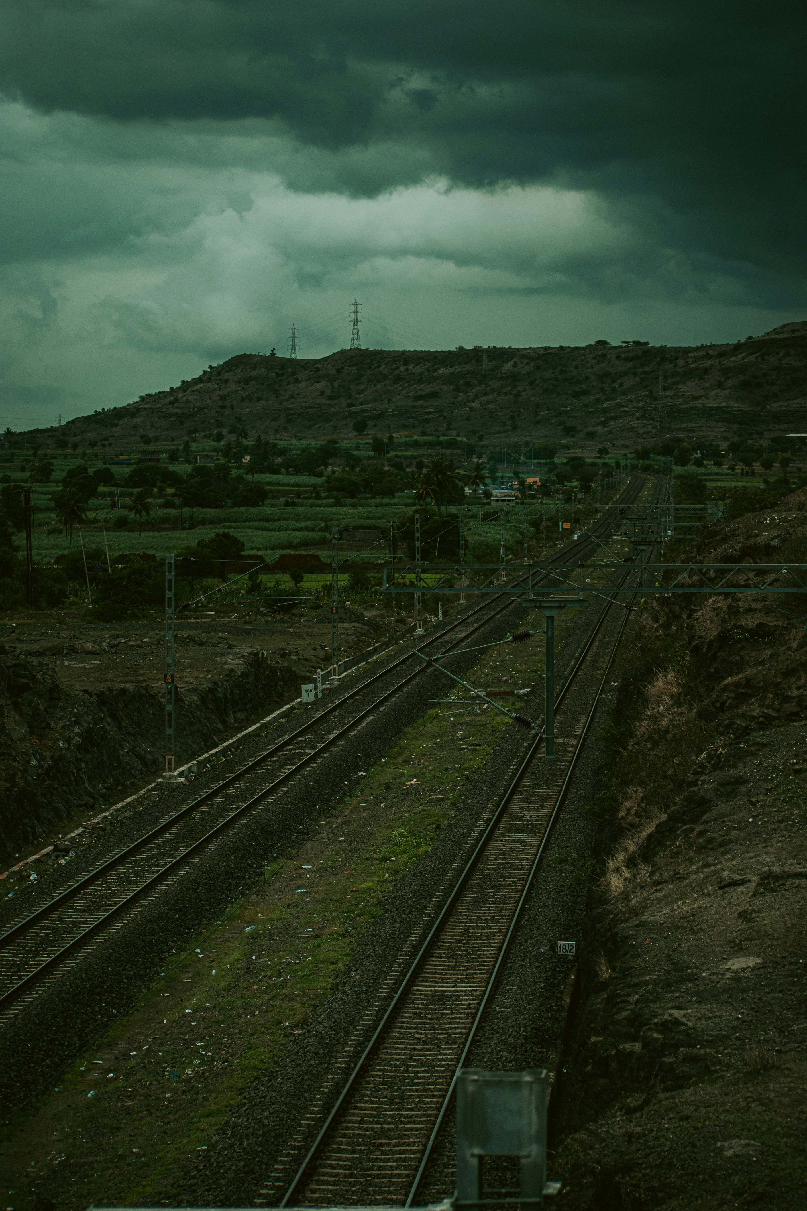 Verdant Rails: A Vanishing Point Beneath Stormy Skies