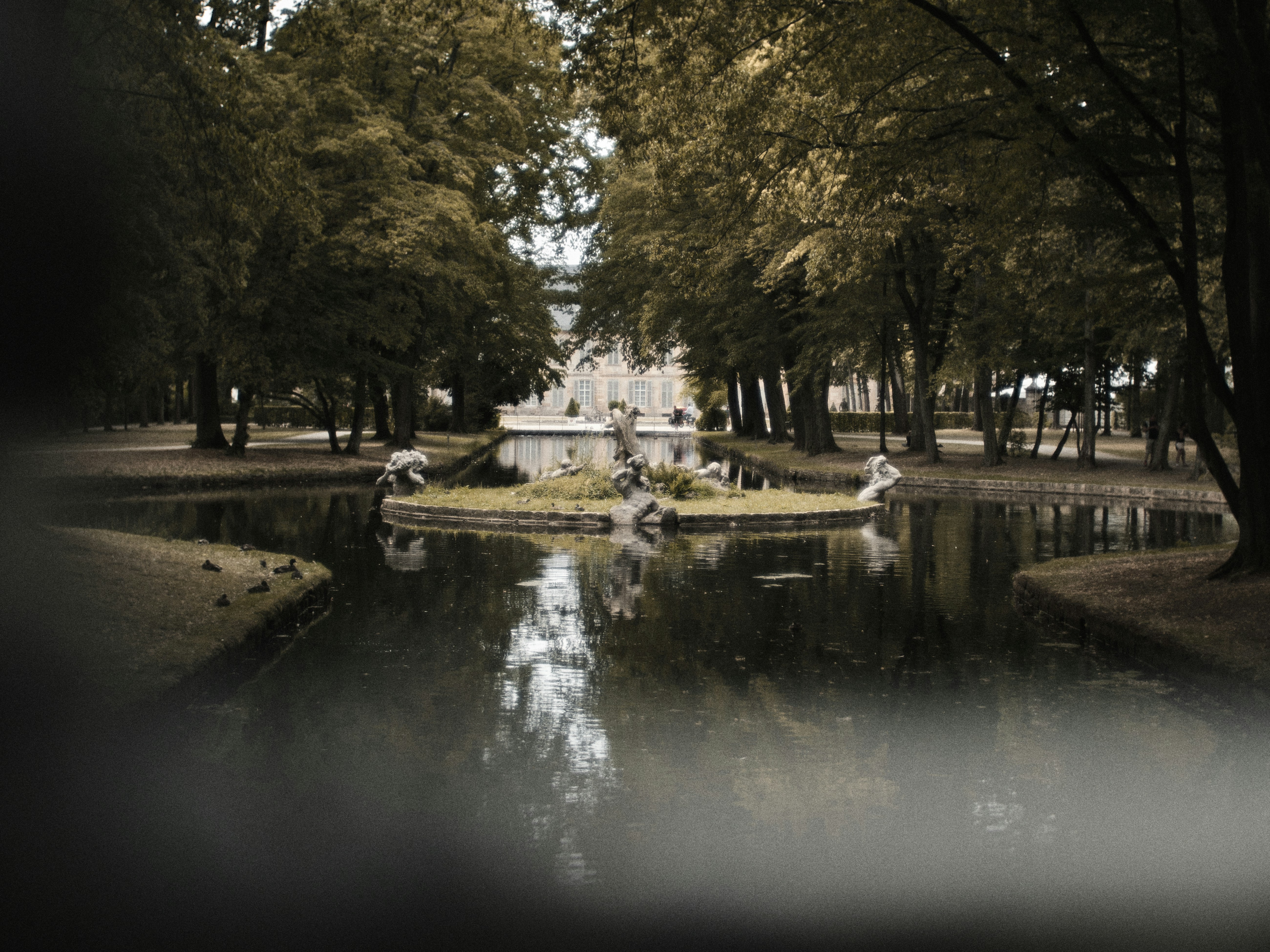 Symmetrical Fountain at Dusk: Reflections in a Tree-Lined Park
