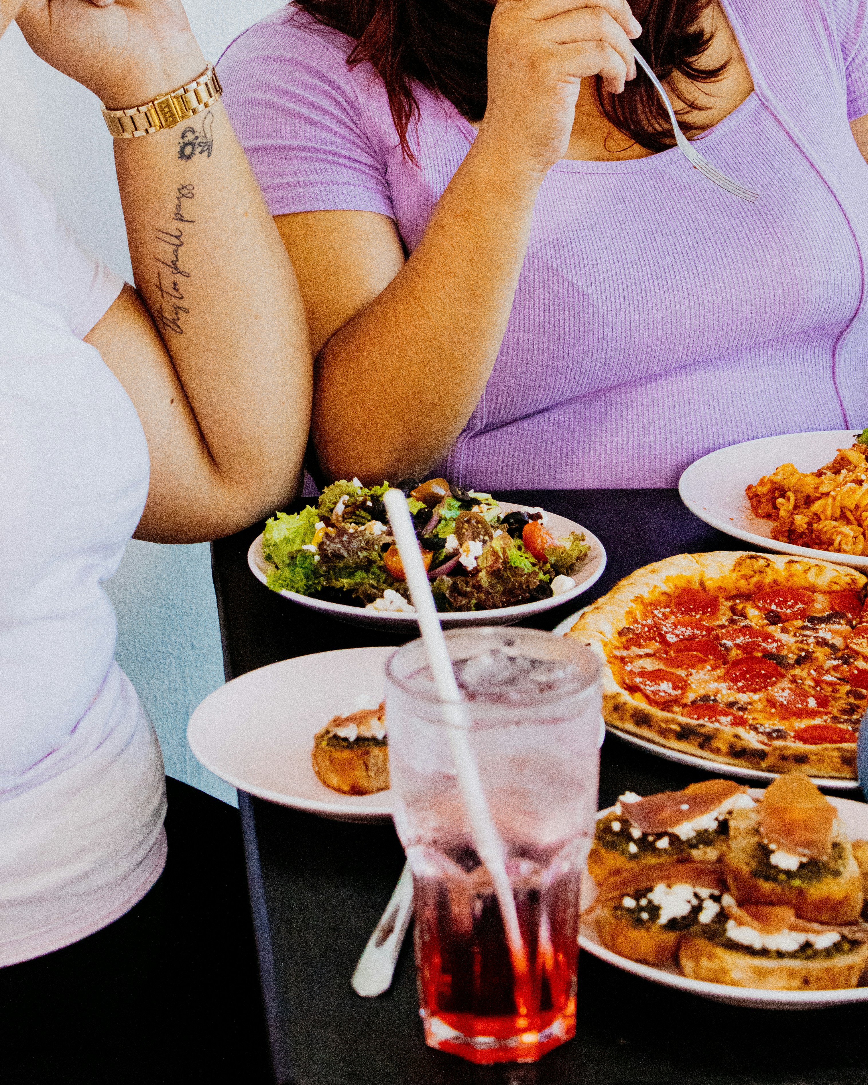 Crimson Drink as Centerpiece in a Shared Pizza-and-Salad Spread