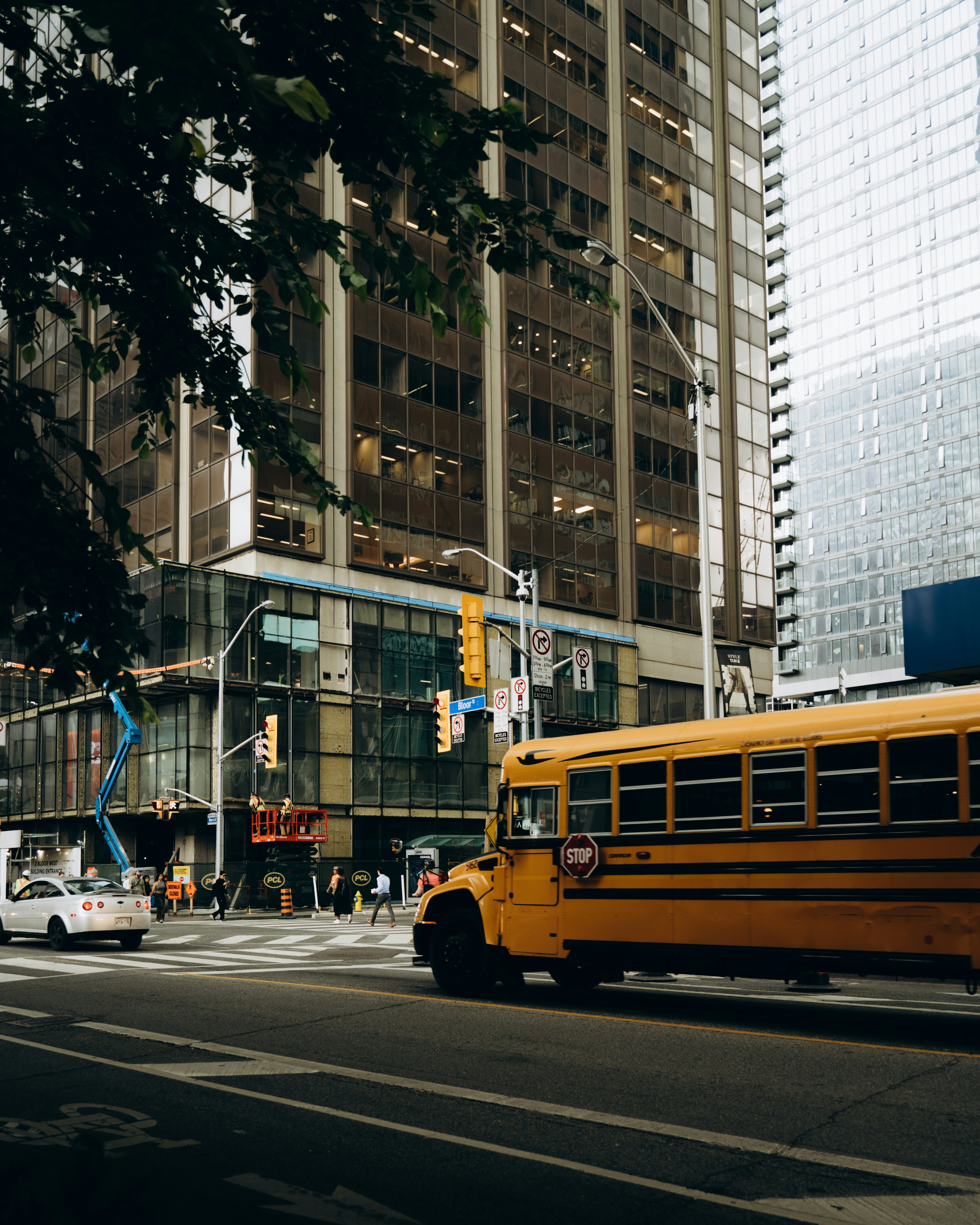 A yellow school bus driving down a street next to tall buildings photo ...