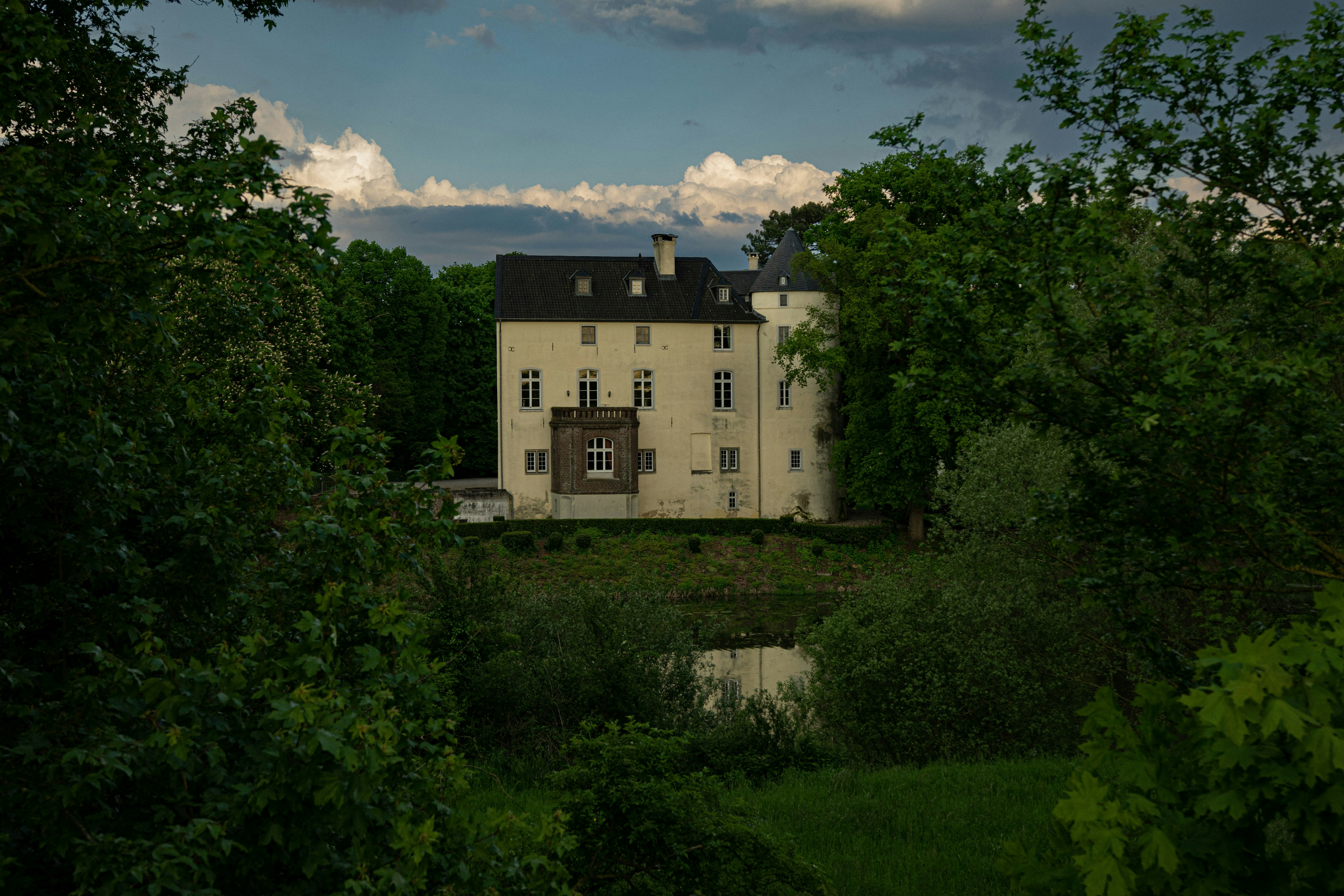 Historic castle framed by lush greenery under a partly cloudy sky.