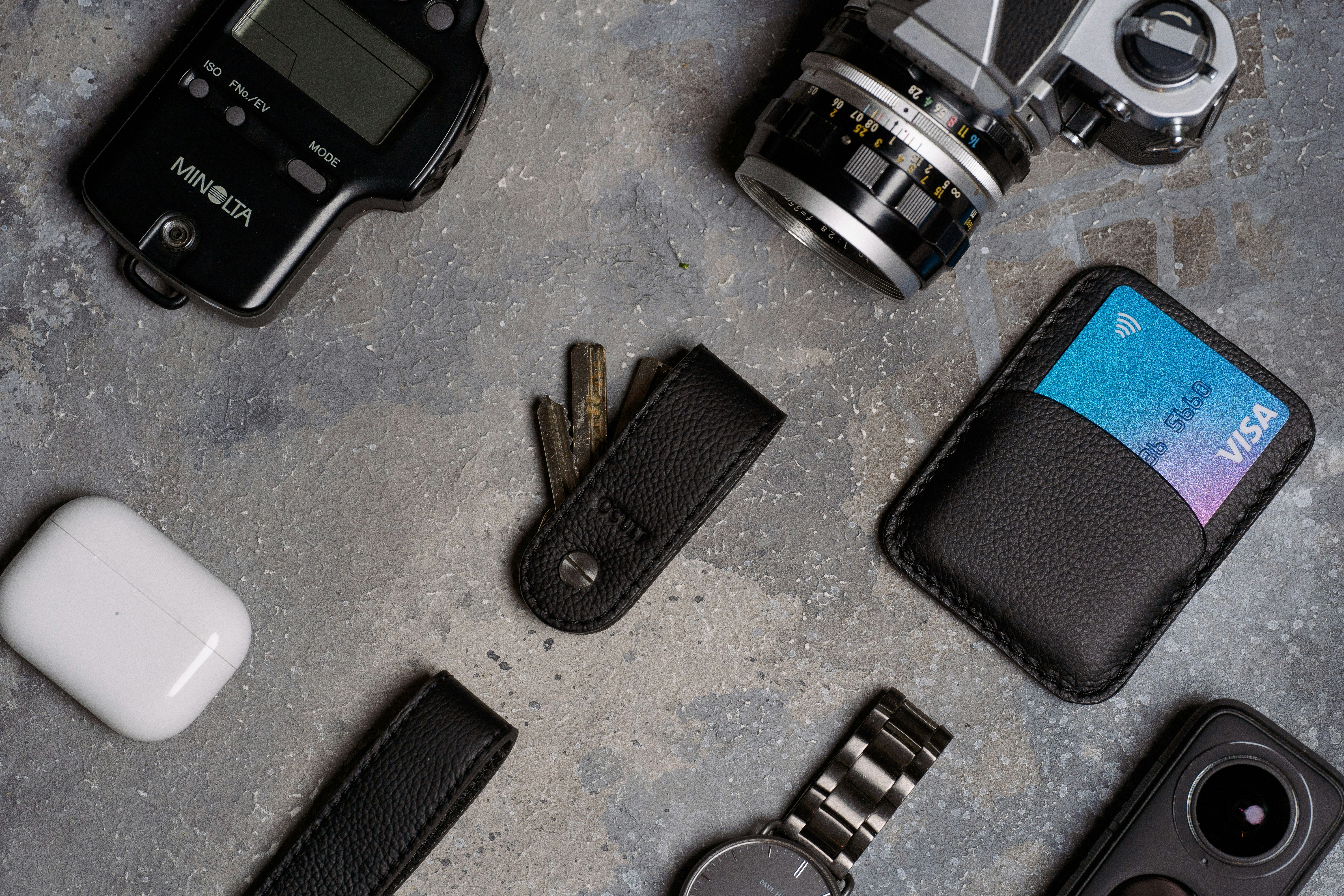 A camera, wallet, keys, and other items laid out on a table photo ...