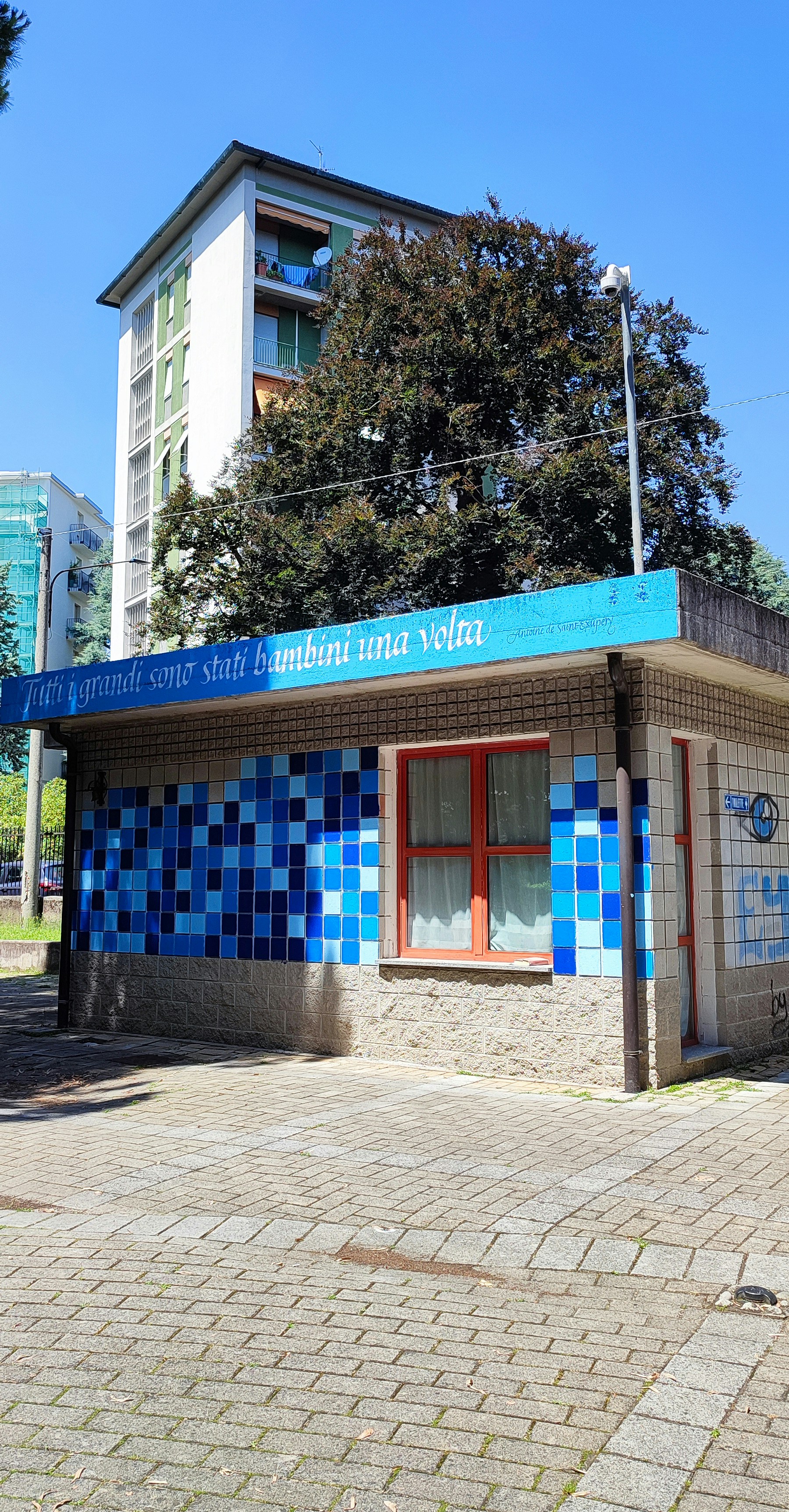 Azure Tiles and a Red Window: A Quiet Street Facade Under a Clear Sky
