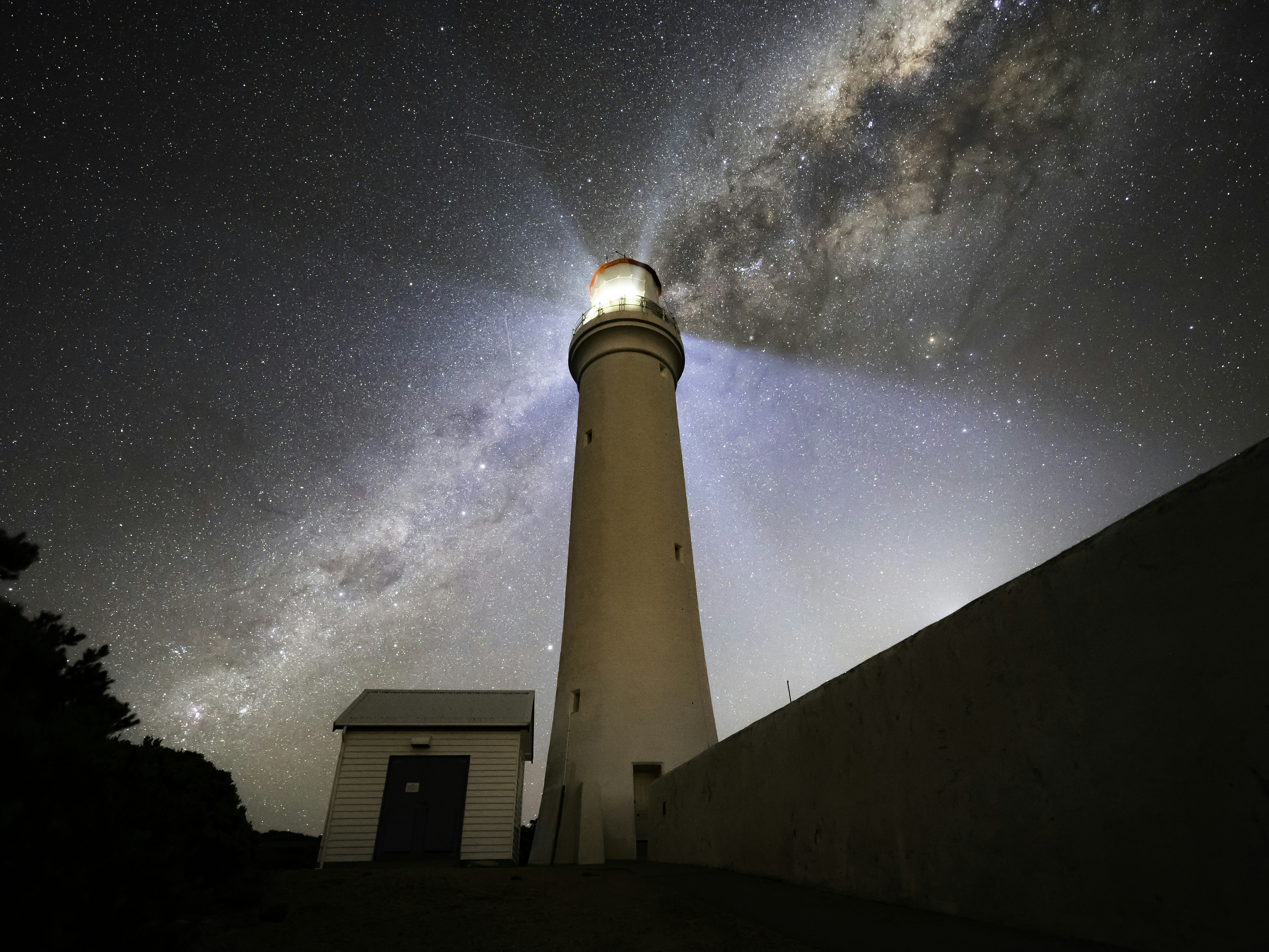 A lighthouse under a night sky filled with stars photo – Free Night ...