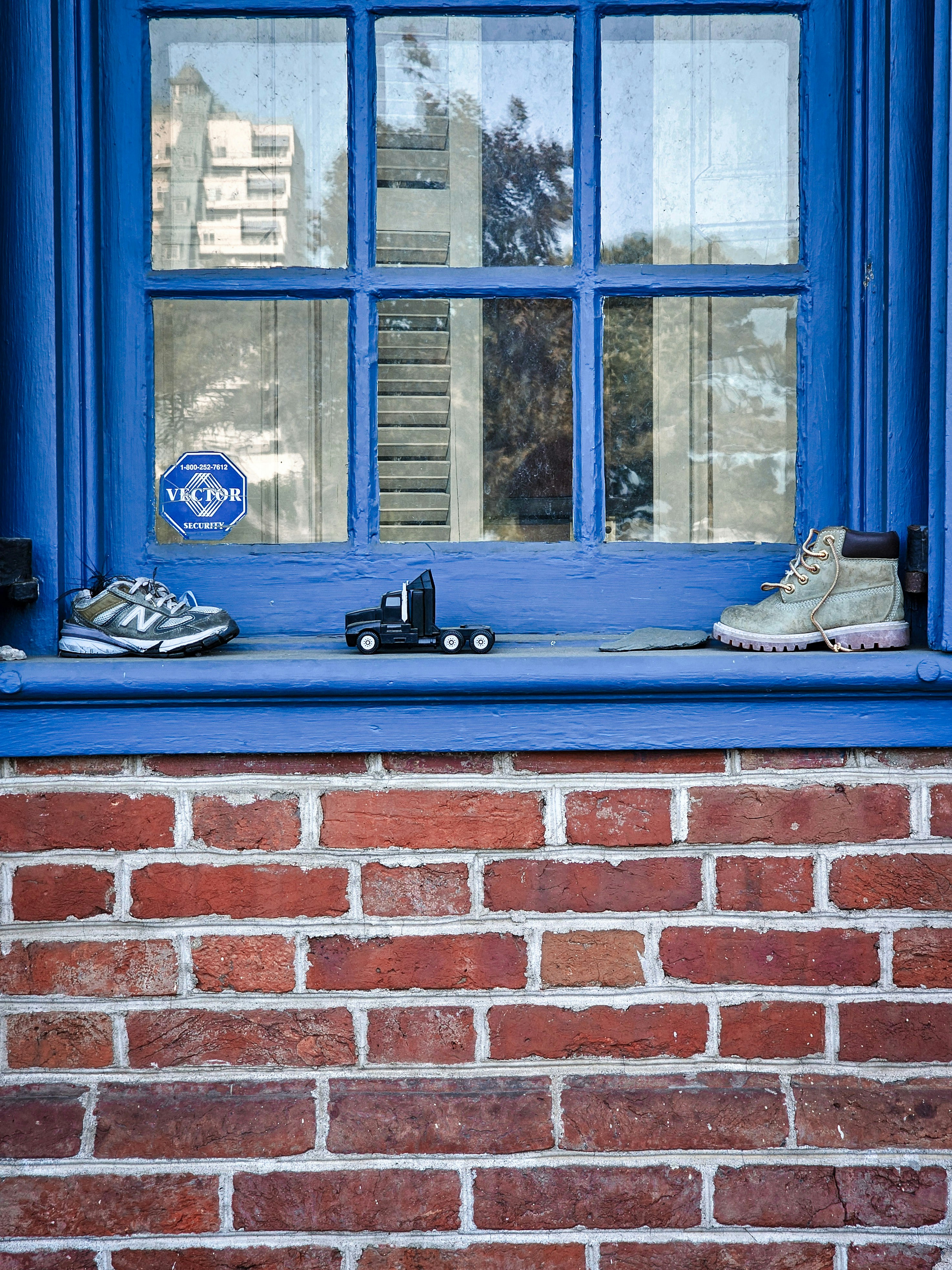 Tiny Truck on a Blue Window Ledge Between Sneakers