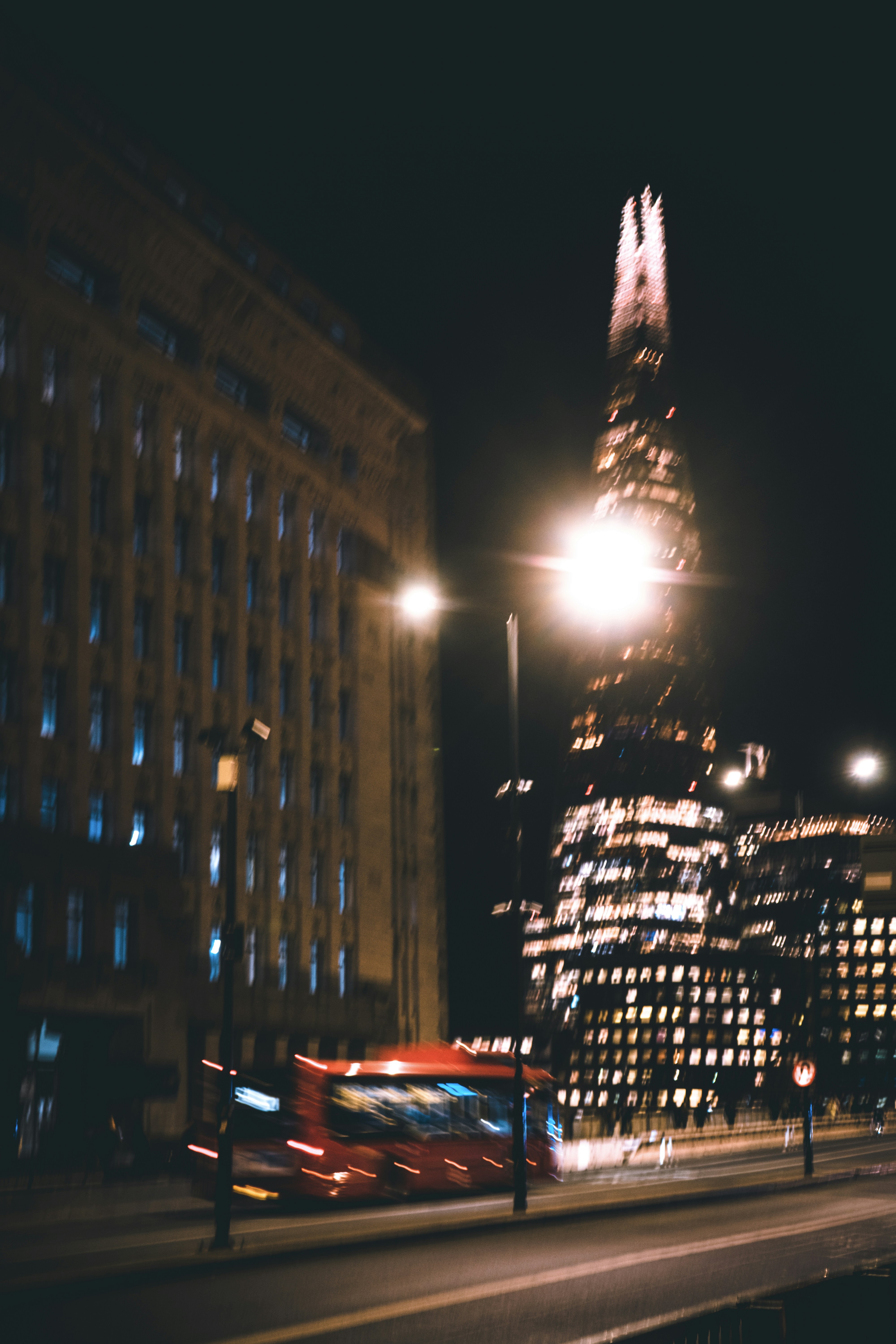 A red bus driving down a street next to tall buildings photo – Free Uk ...
