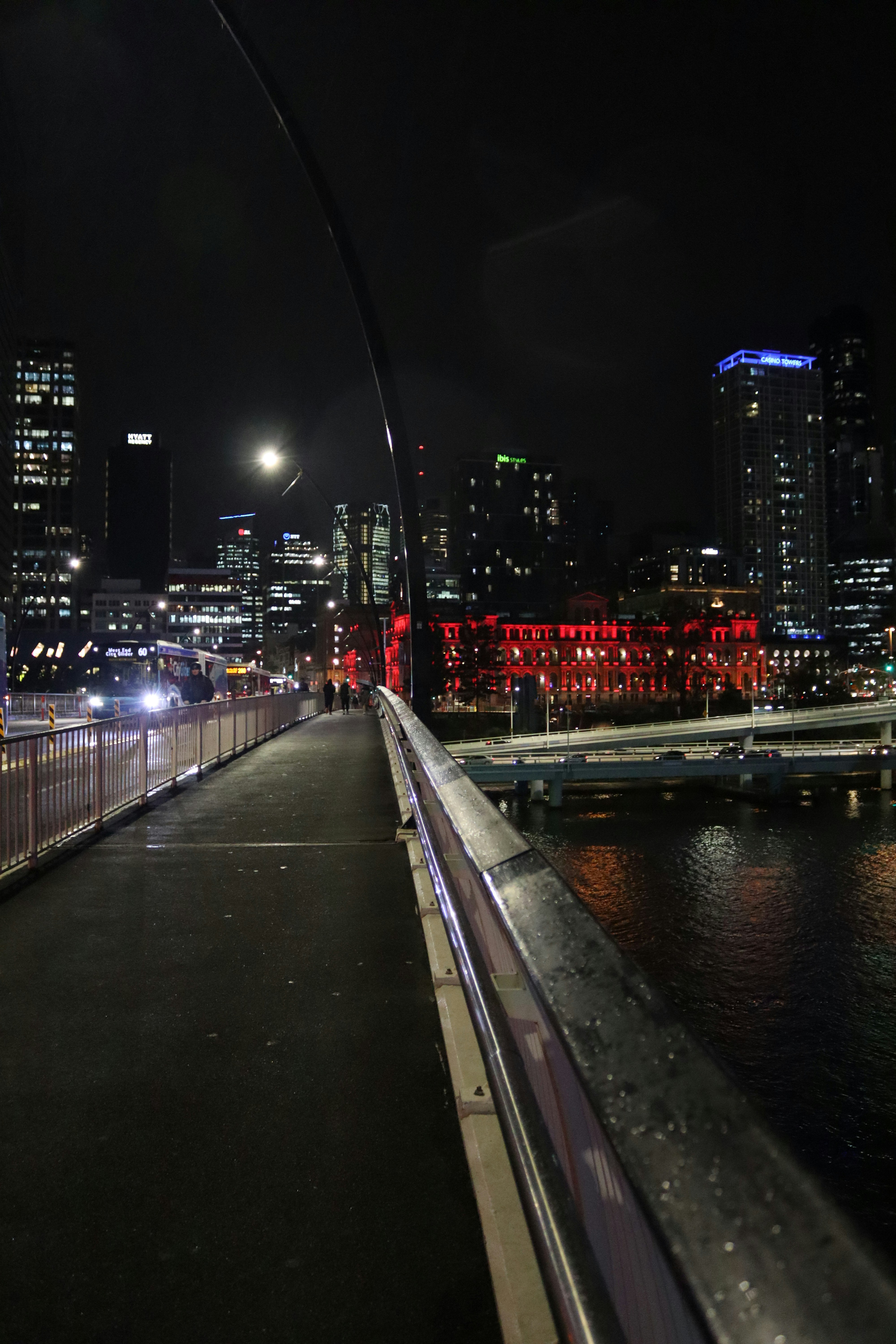 Bridge of Neon Currents: Night Walk Toward the Riverfront Skyline