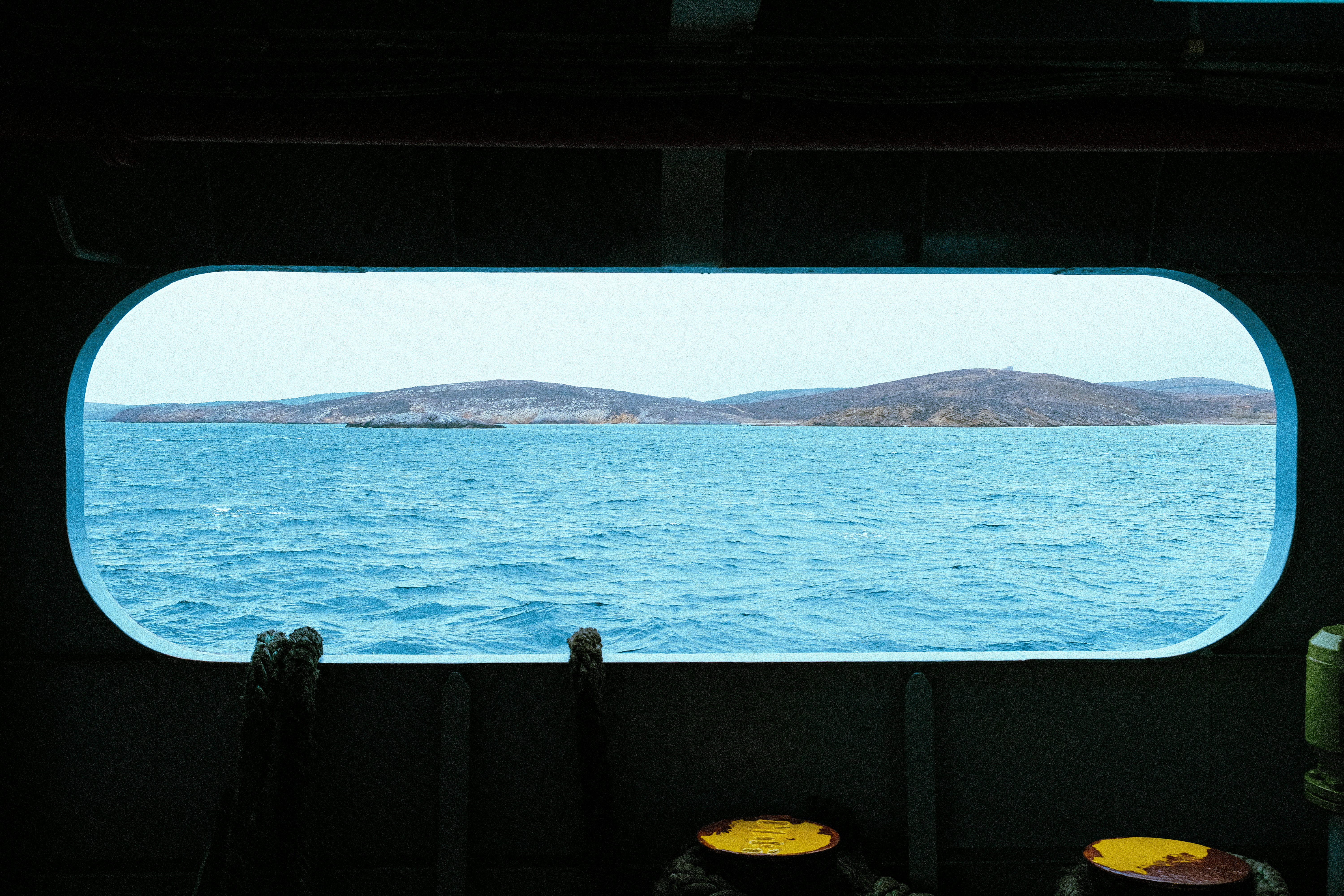 View of tranquil islands and blue sea through a ferry window.