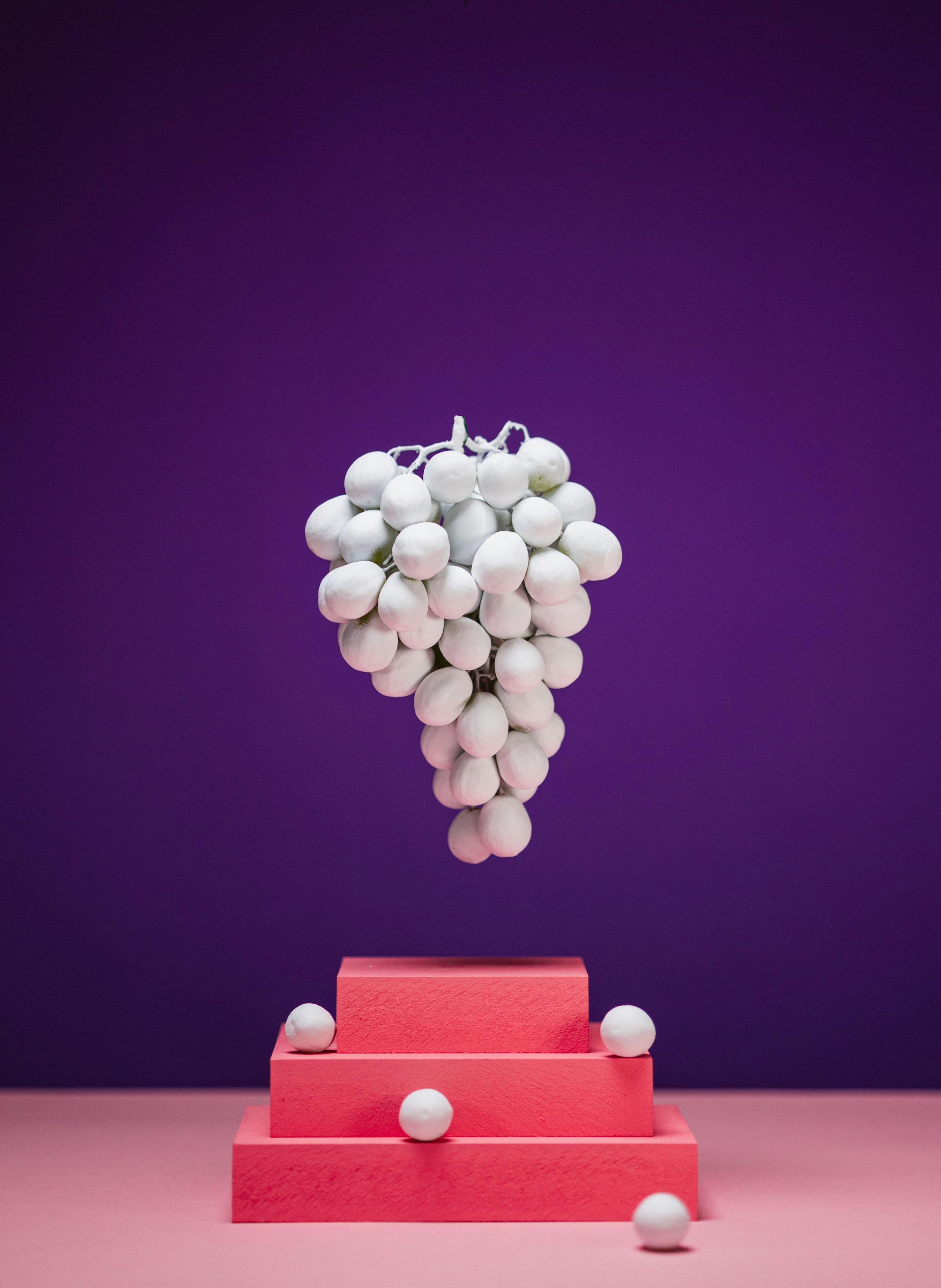 Gravity-Defying Grapes Hover Over Pink Steps in a Velvet Purple Studio