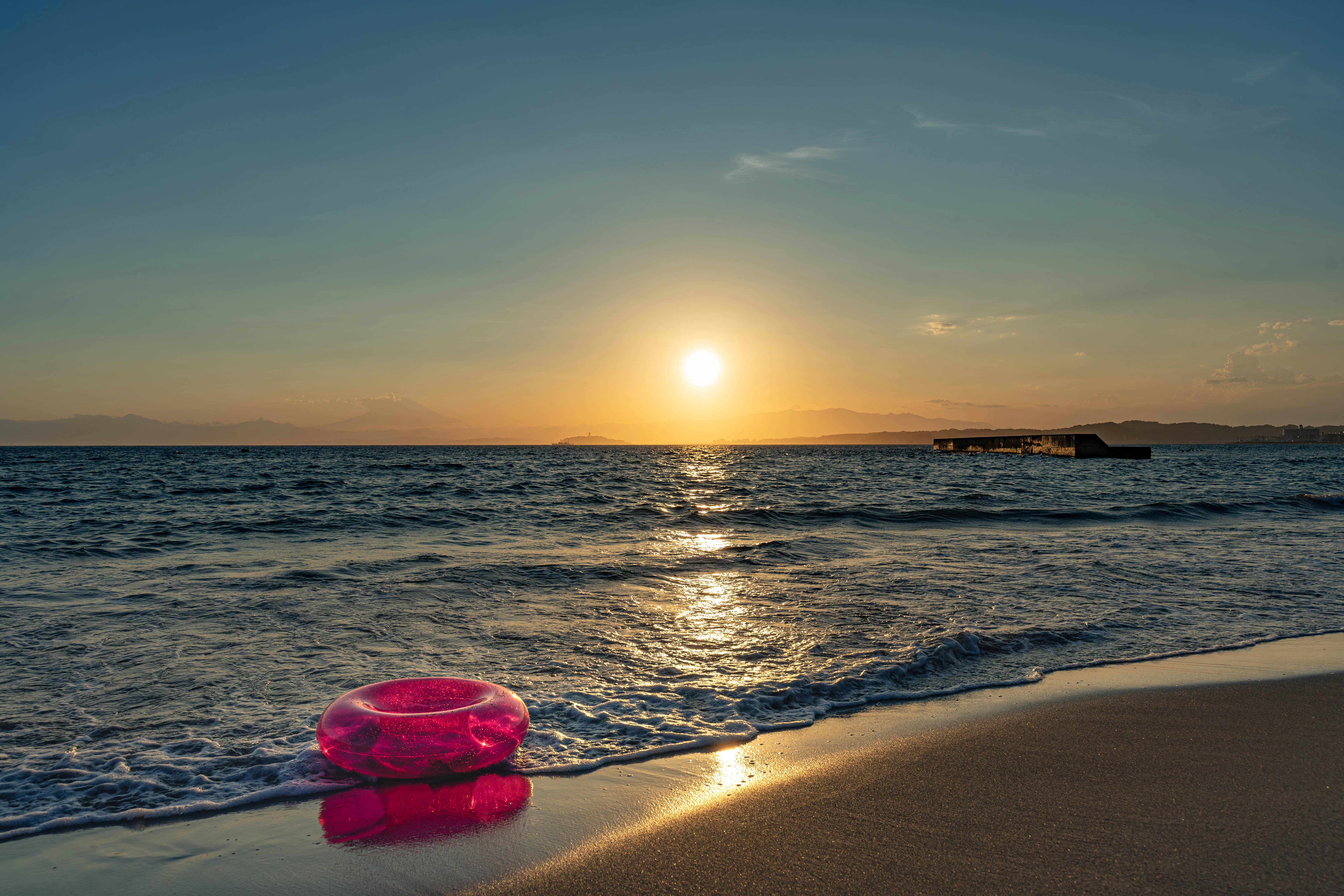 Pink Inflatable Ring at Dusk: Quiet Shoreline in Golden Light