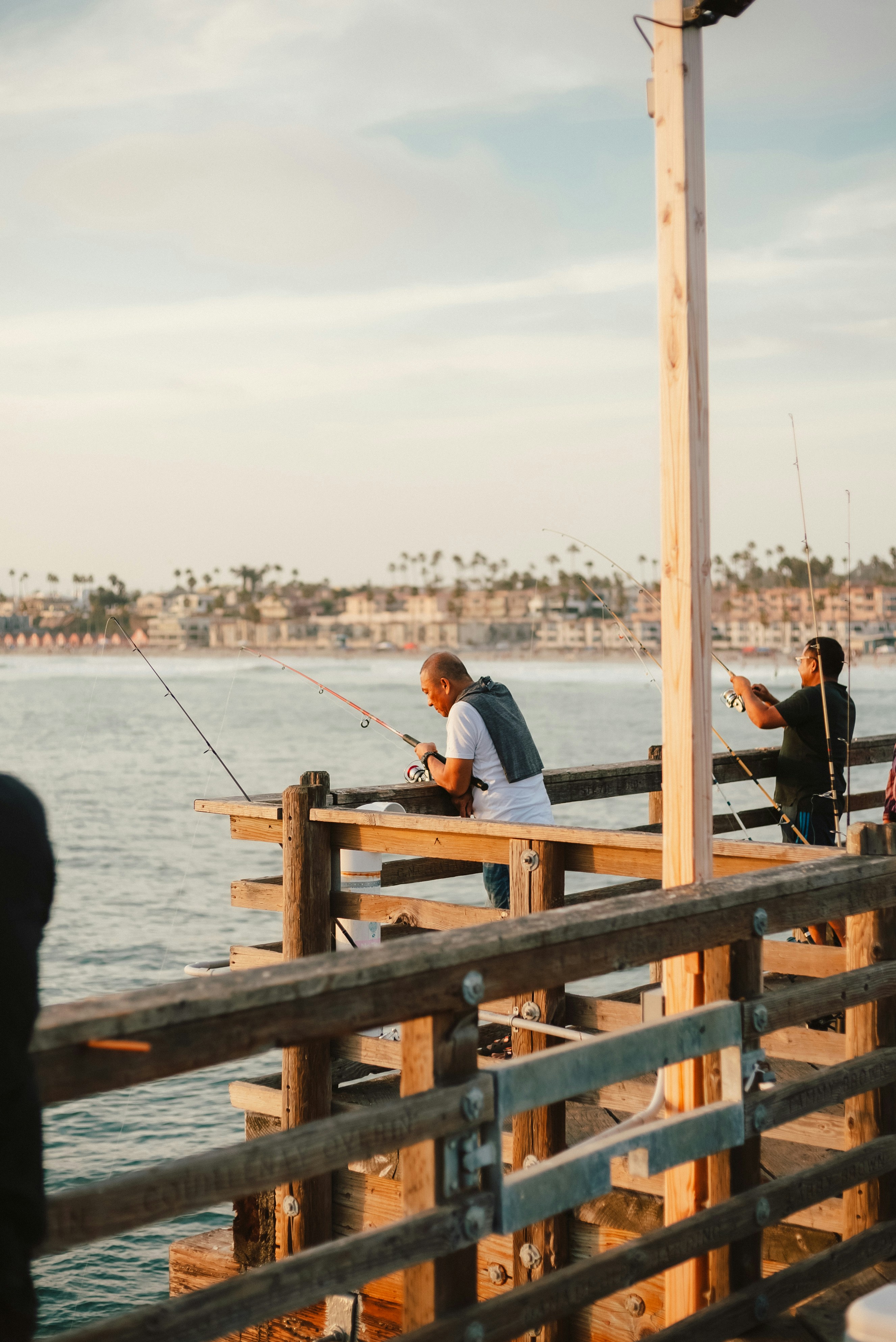 A group of men standing on top of a pier photo – Free Beach Image on ...