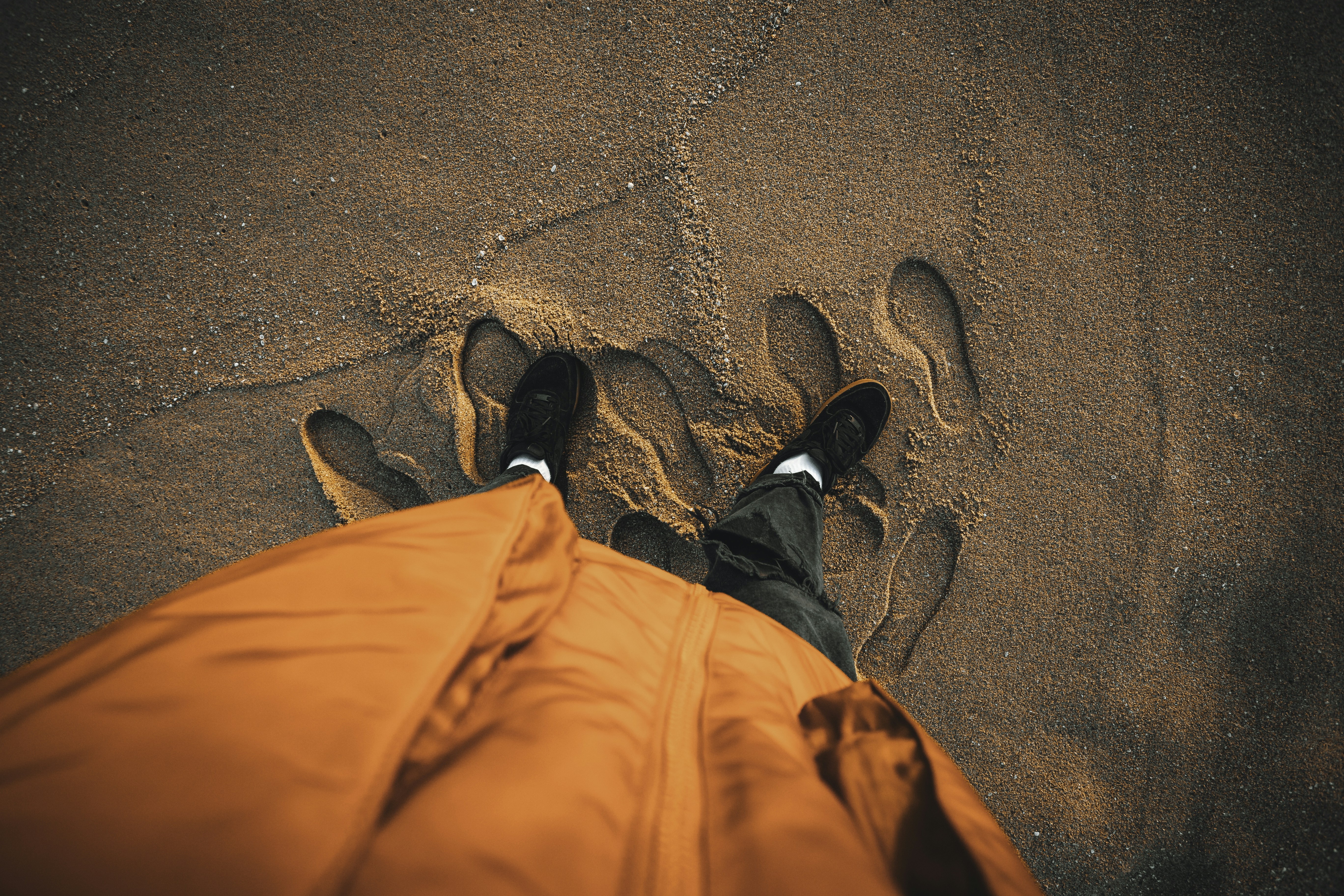 Overhead Orange: Footprints Leading Across Wet Sand