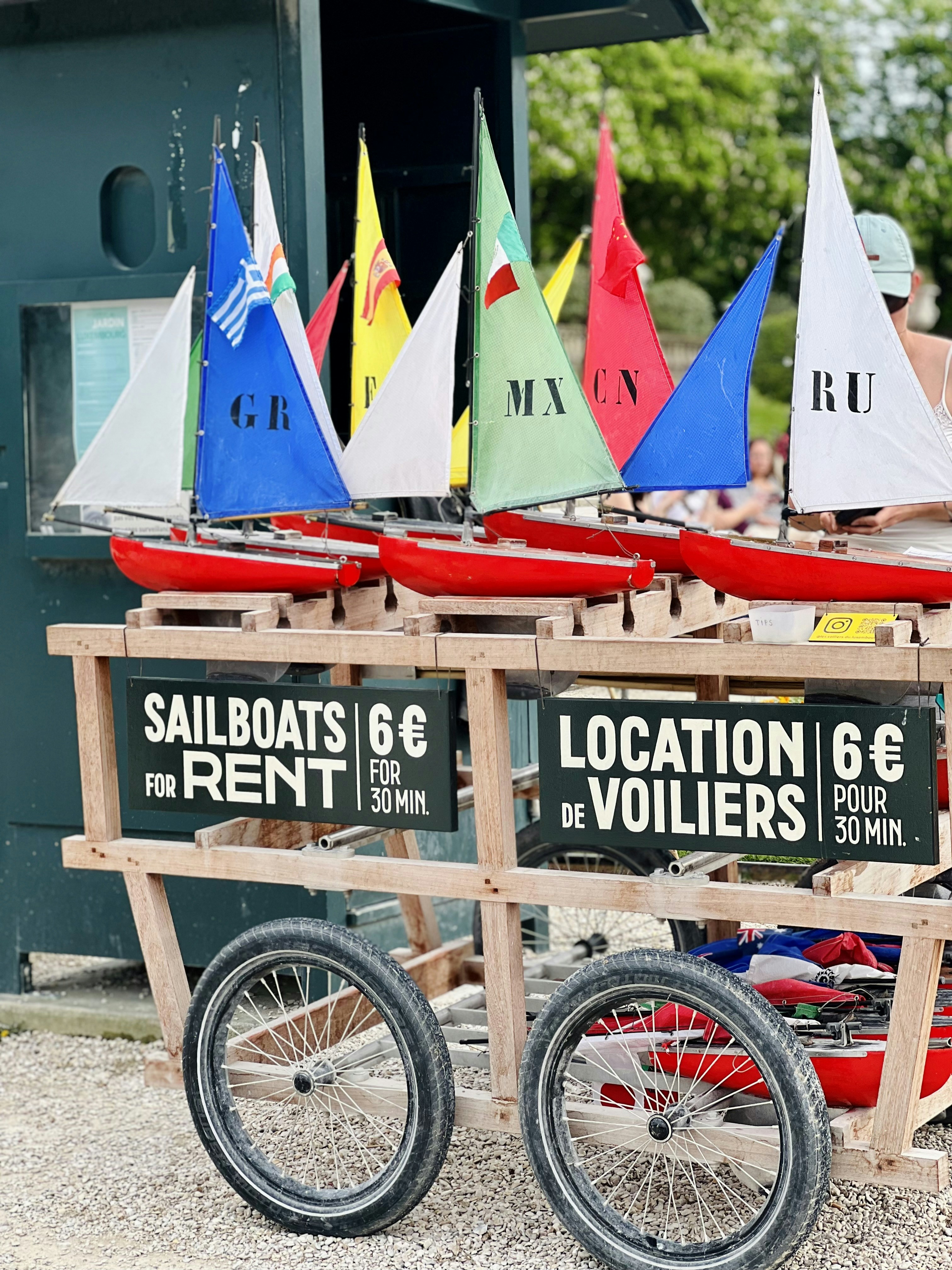 Colorful sailboats on a wooden rental cart at a seaside stall